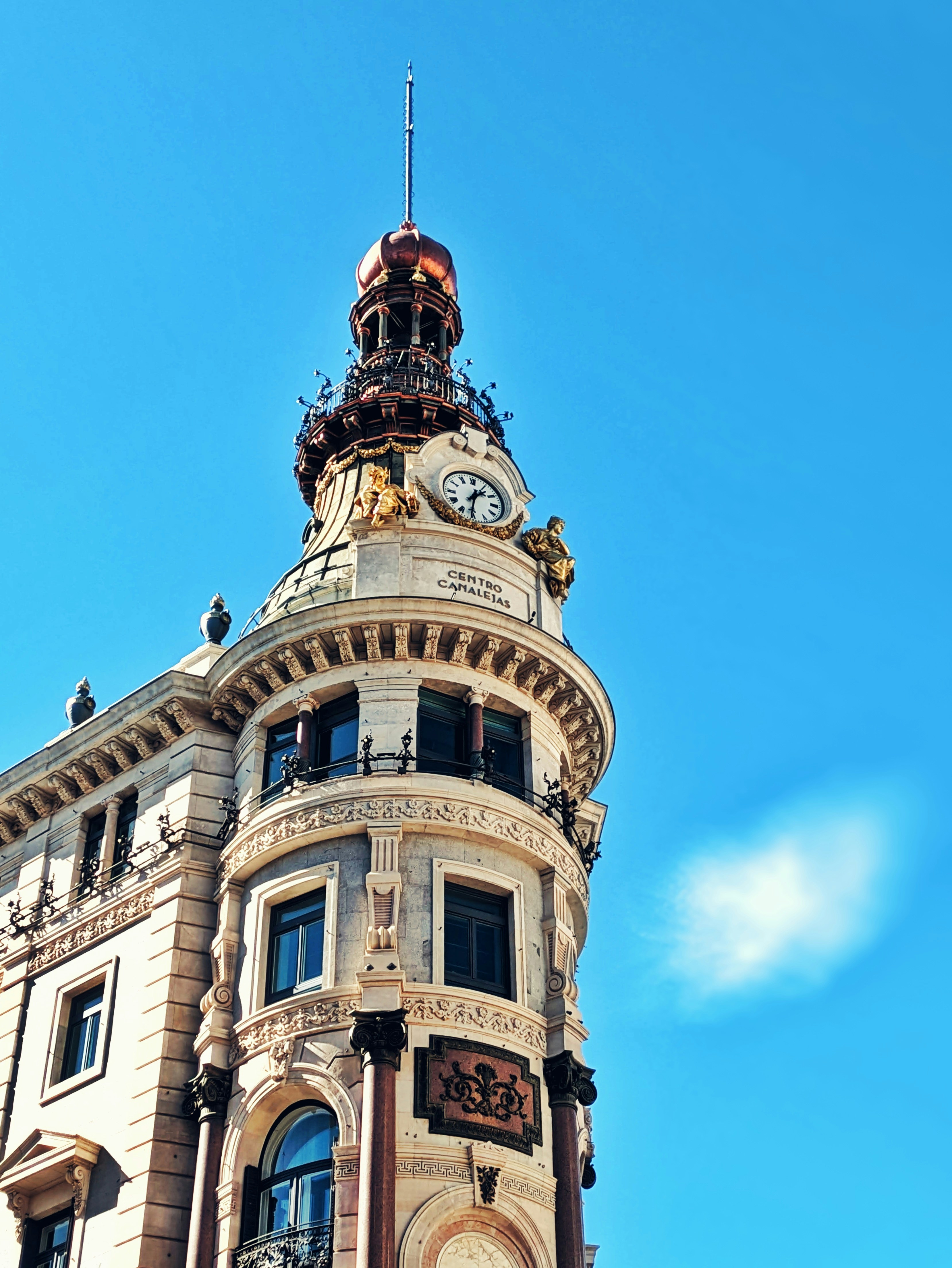 Step back in time with the stunning Building of the Spanish Credit Bank in Madrid! 🏛️ Built between 1887 and 1891, this eclectic masterpiece once served as the Palace of Justice. Its iconic facade features majestic elephant heads supporting the first-floor balcony, while a striking semicircular corner crowned with a clock tower and bandstand steals the show. A true architectural gem in the heart of Madrid! | A tall building with a clock on the top of it