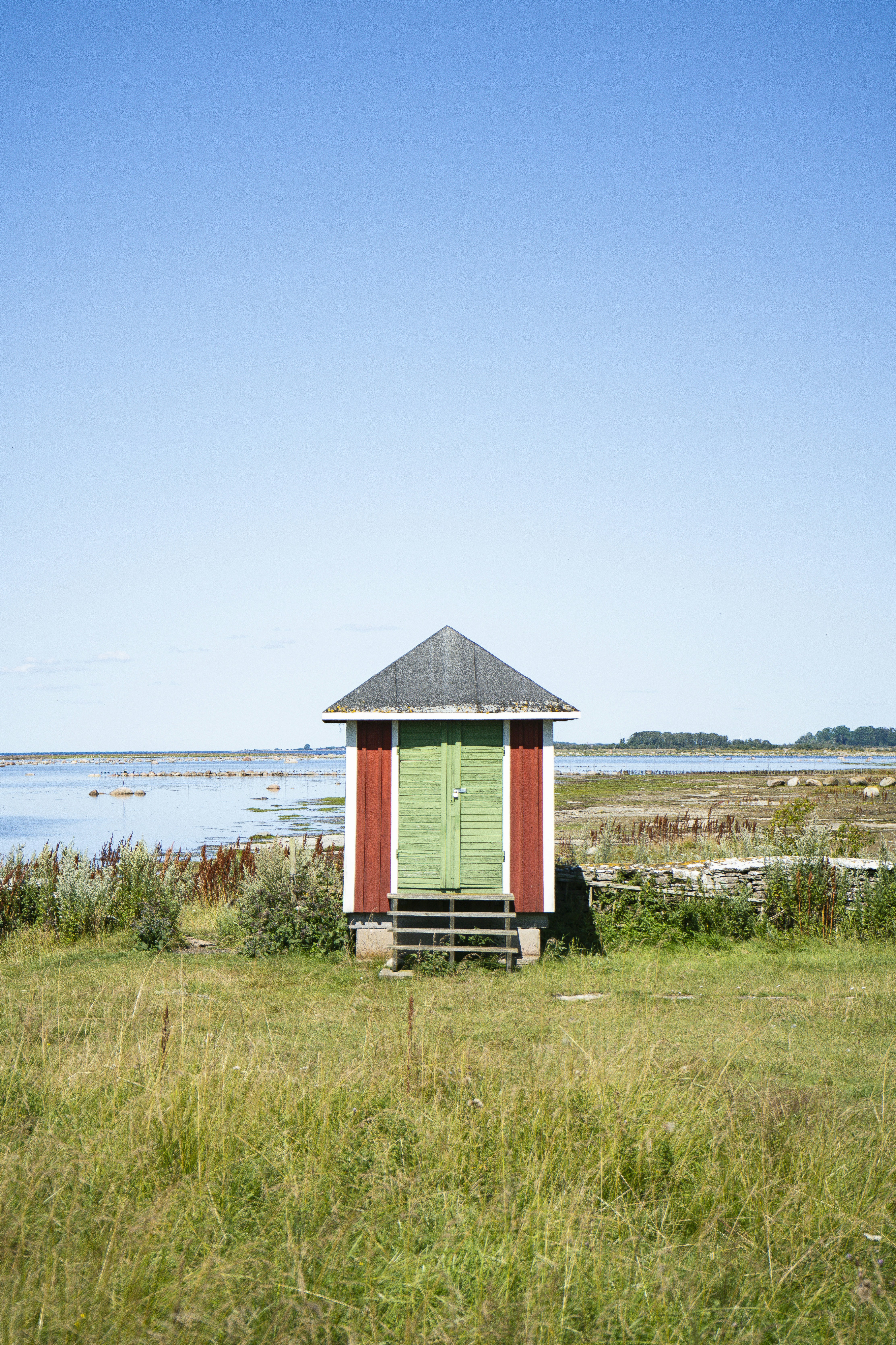 A small red and green hut sitting in a field photo – Free House Image ...