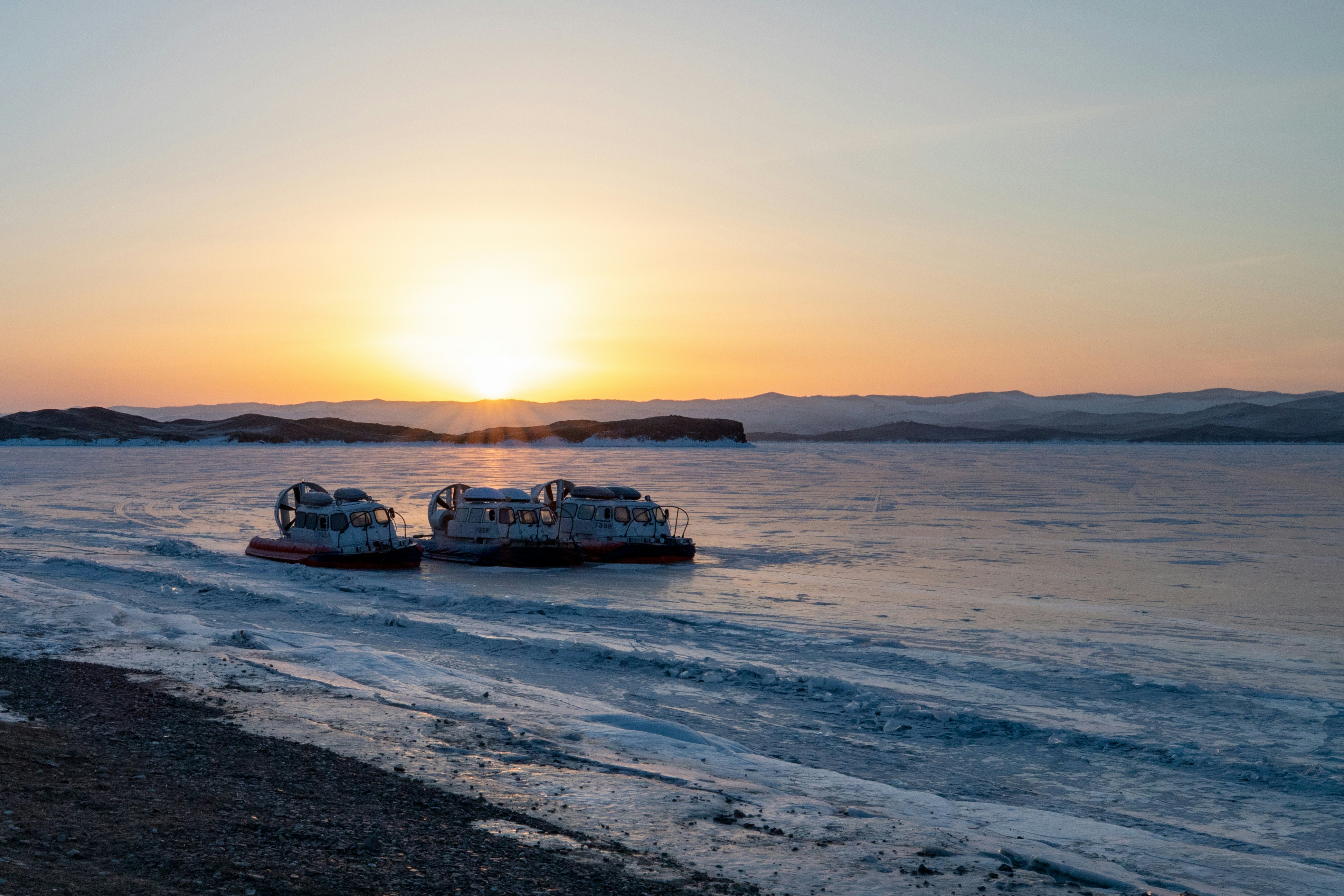 Dusk on a Frozen Fjord: Twin Hovercrafts Rest Against a Copper Sunset