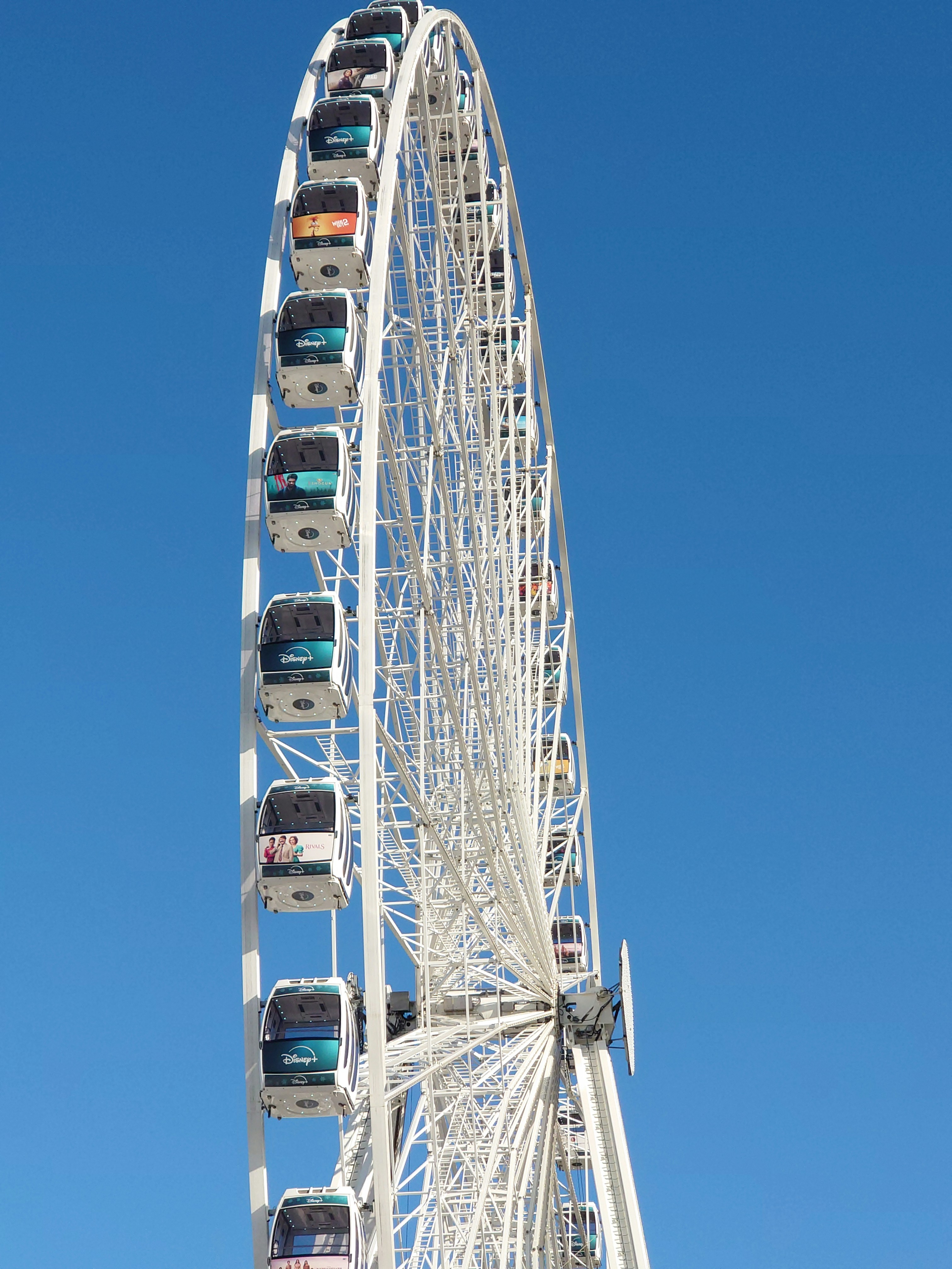 A ferris wheel with cars on it against a blue sky photo – Free Hyde ...