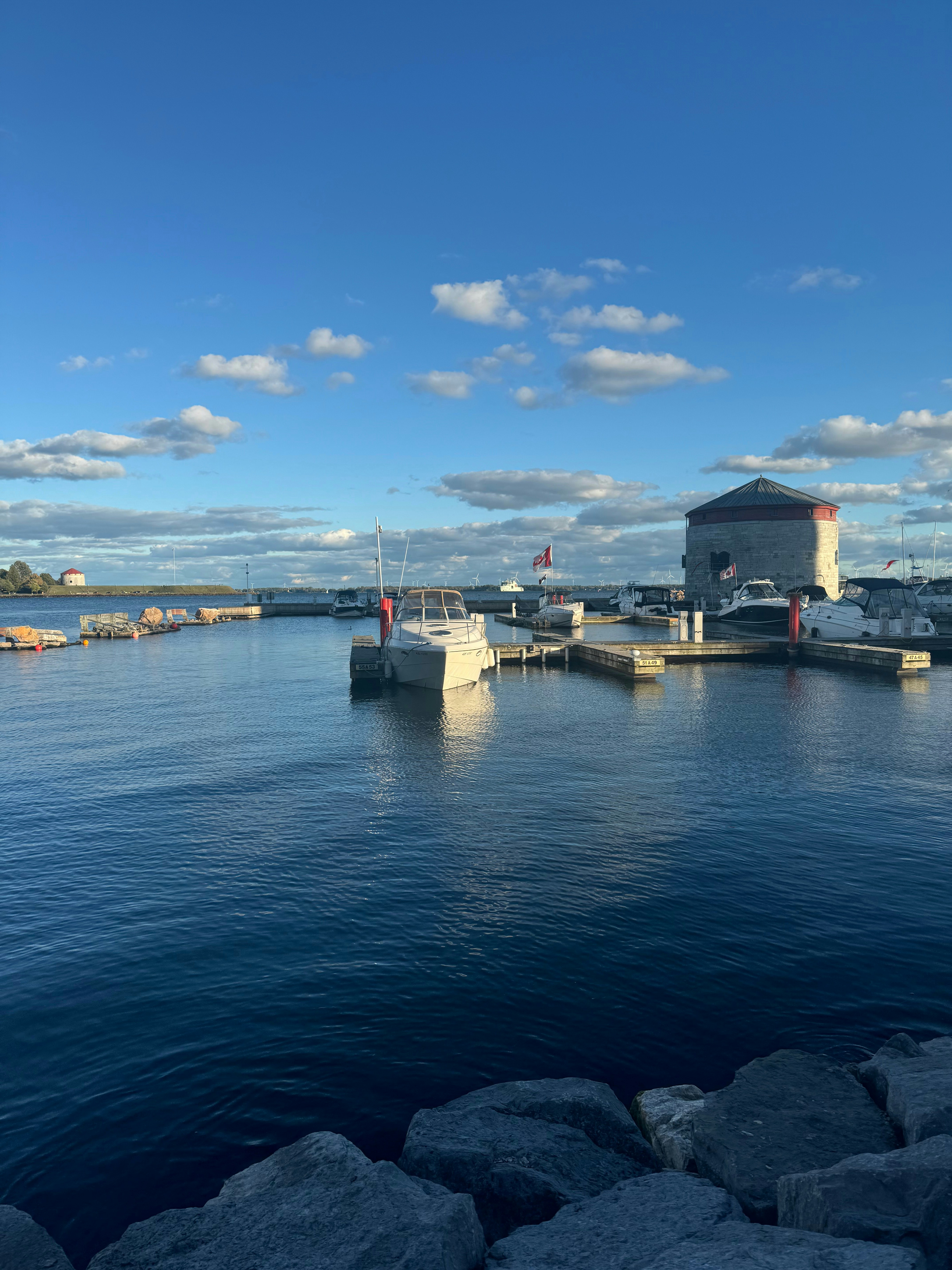 Harbor at Dusk: Boats, Stone Pier, and a Circular Lighthouse Keep