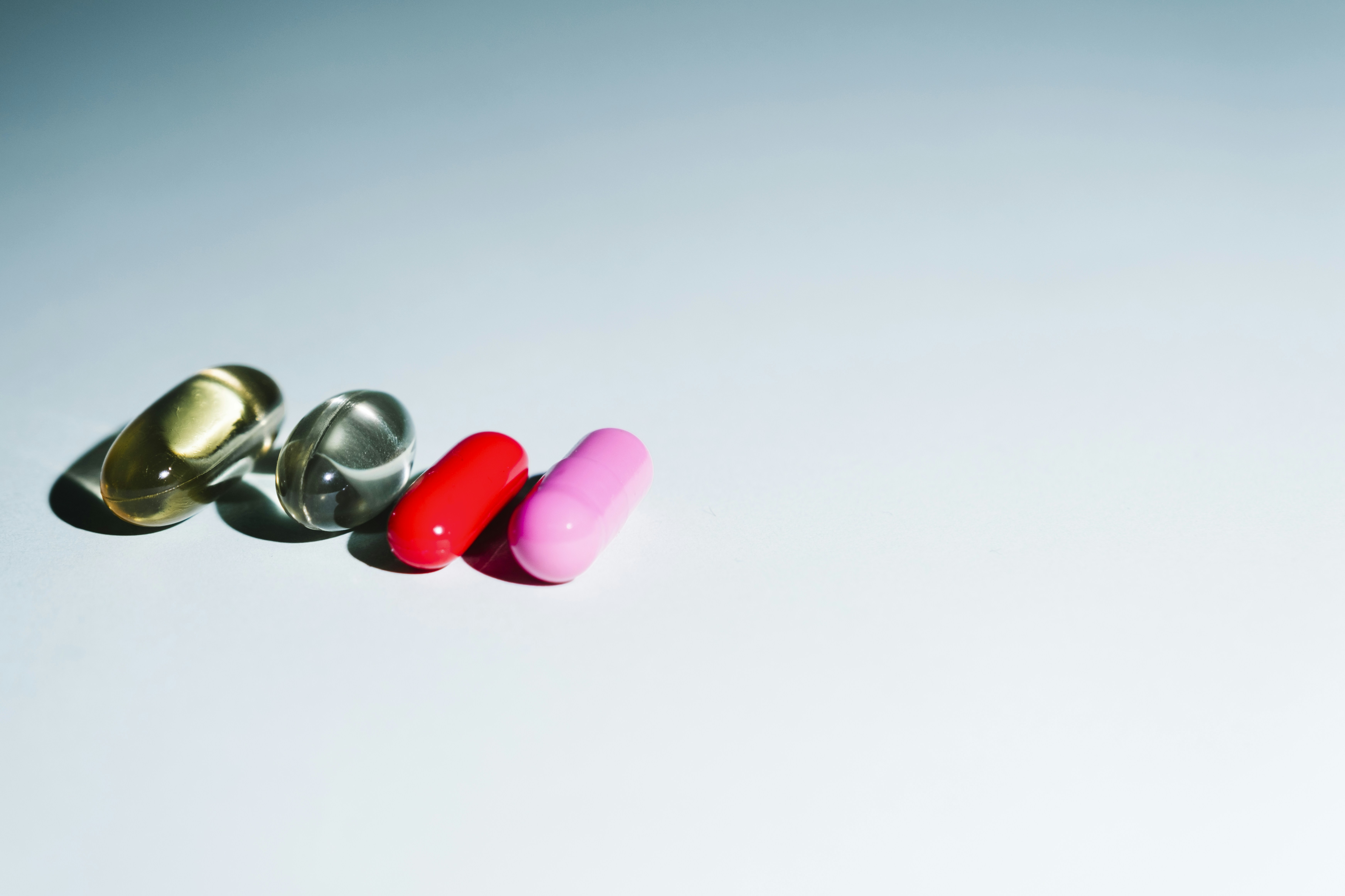 Assorted capsules in vibrant colors arranged on a minimalist surface, highlighting the diversity of medicinal forms.