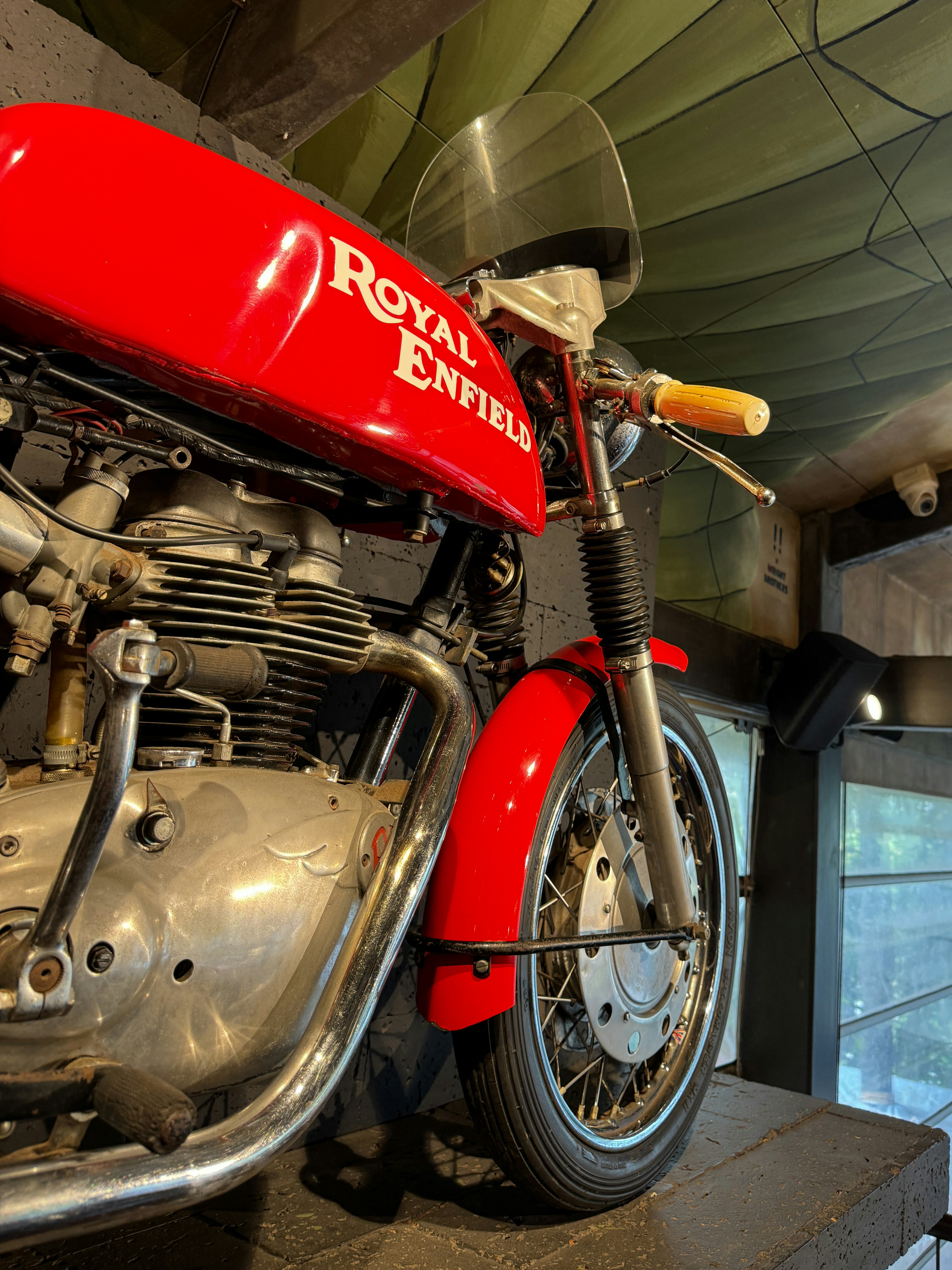 Crimson Royal Enfield in a Dim Workshop: Vintage Power Under Industrial Light