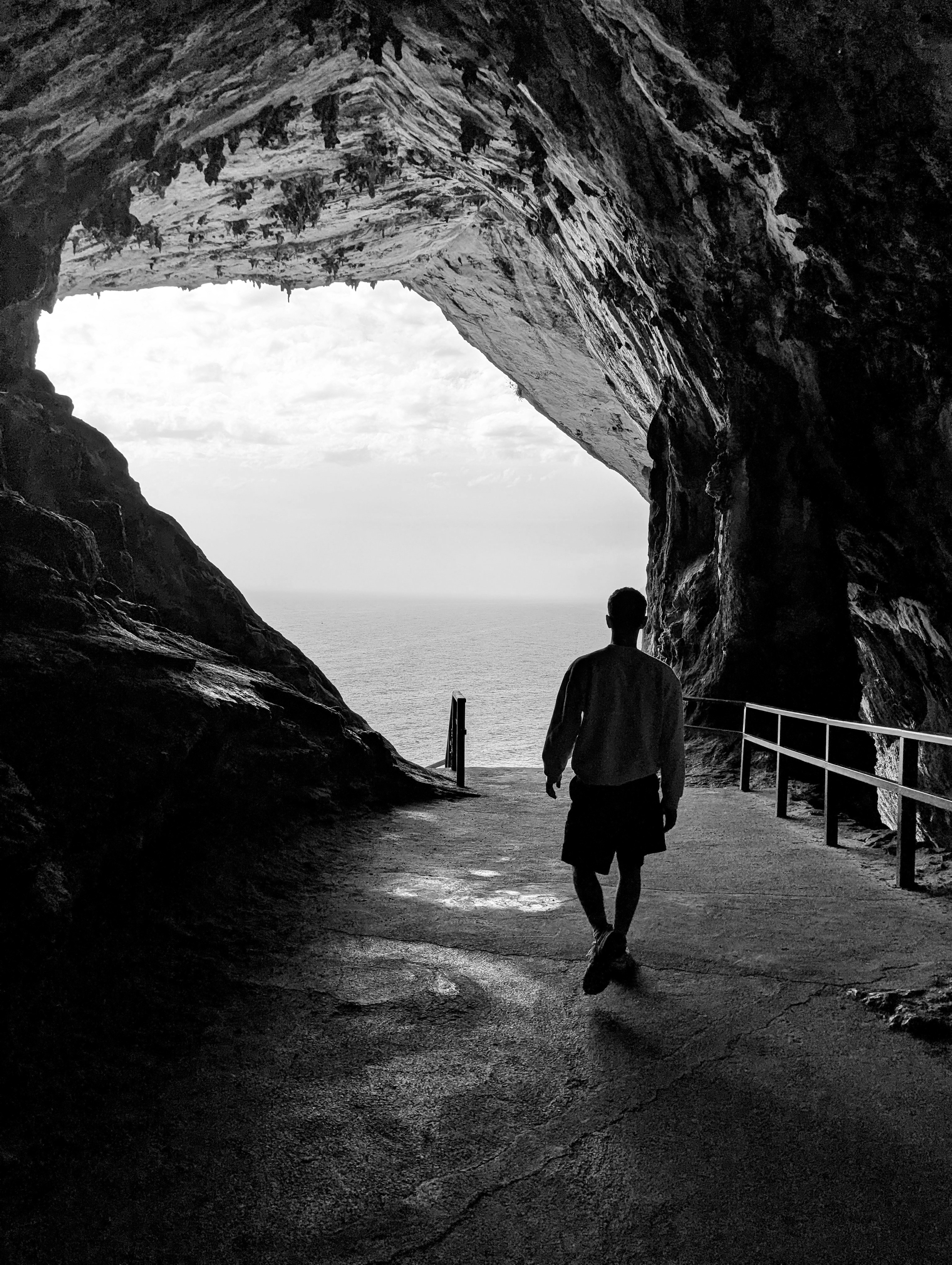 A man walking into a cave next to the ocean photo – Free Mallorca Image ...