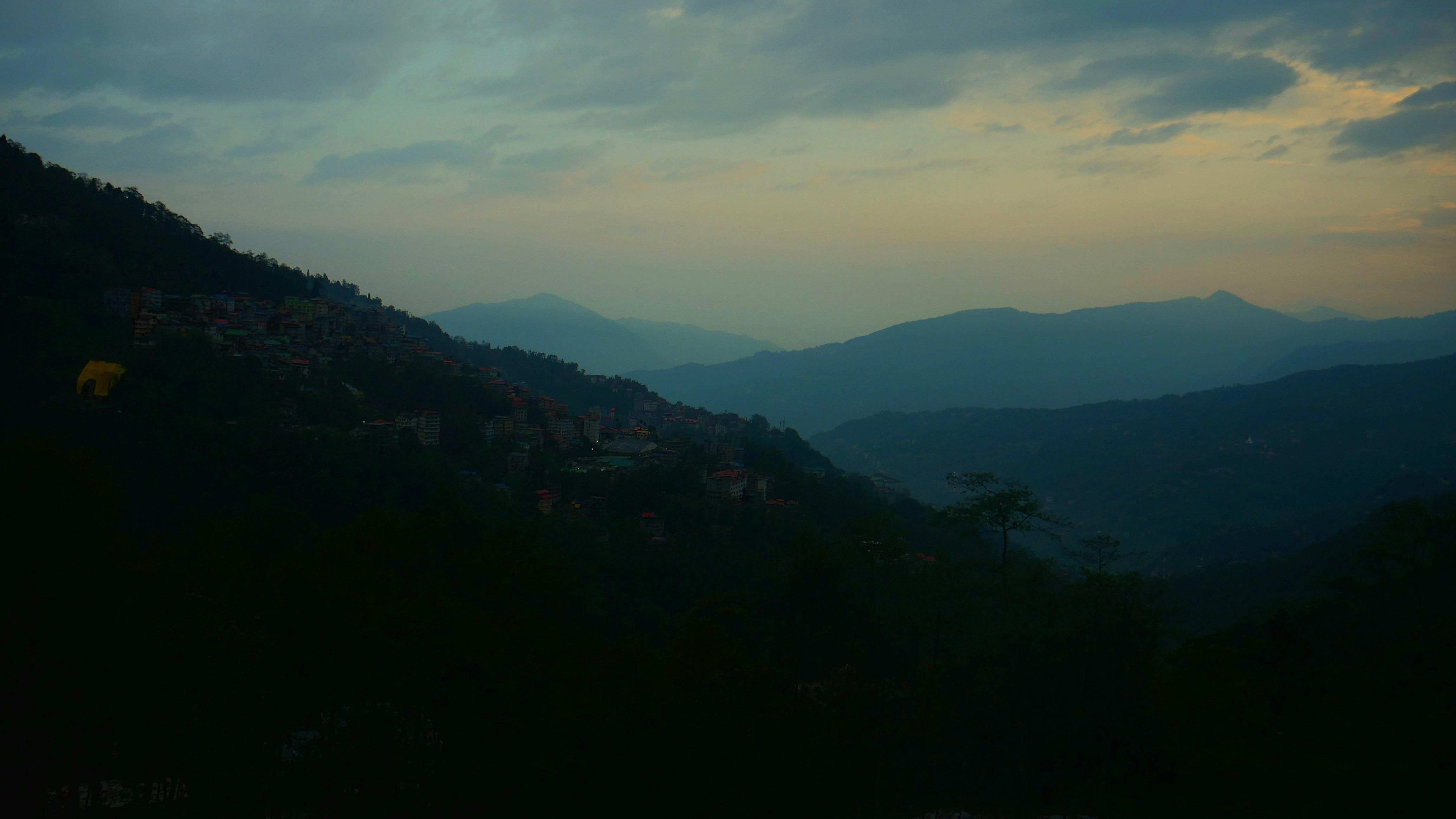 Horizon in Blue: Dusk Over Layered Valleys with a Quiet Village