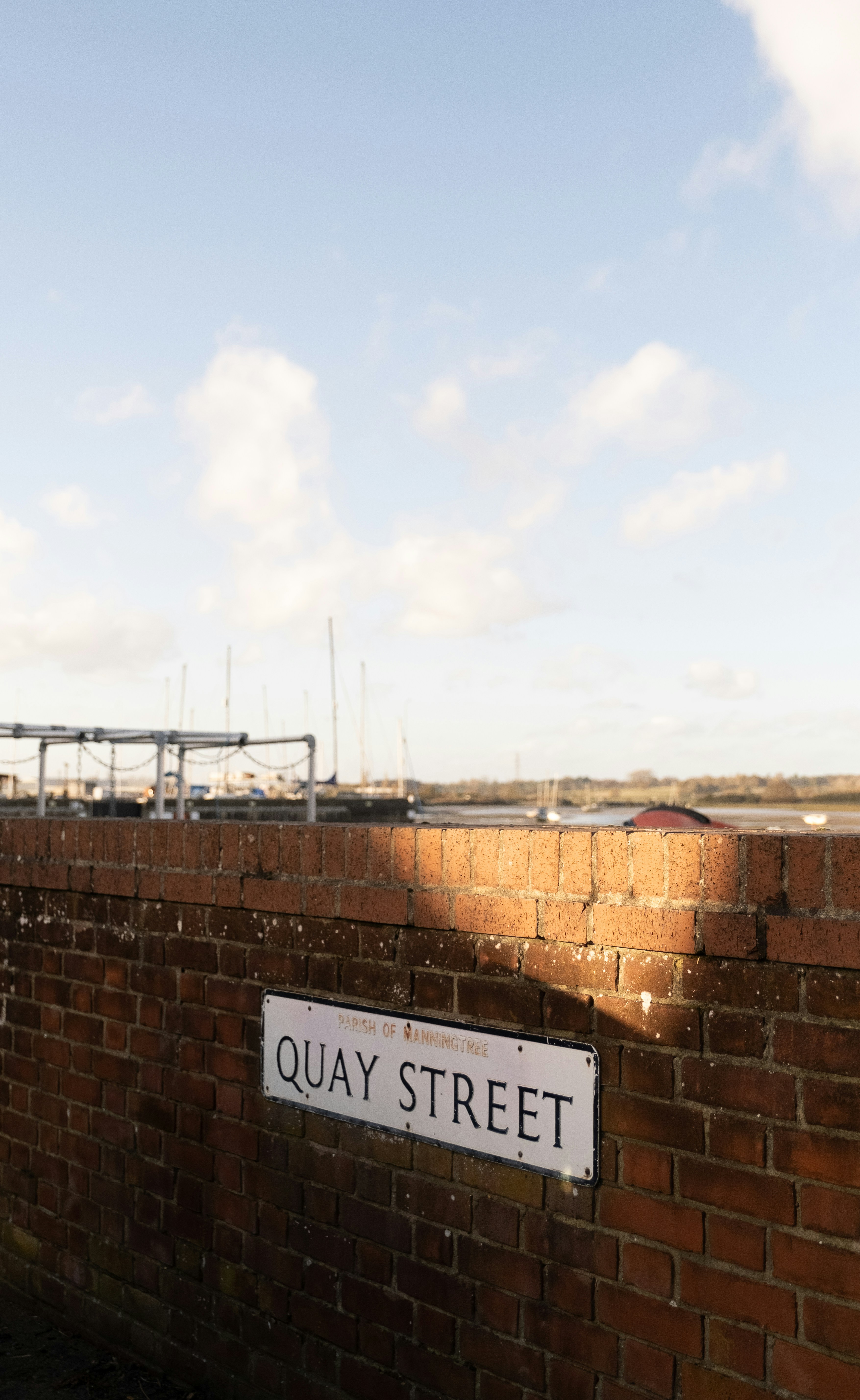Quay Street Sign Framed by Sunlit Brick and Distant Masts
