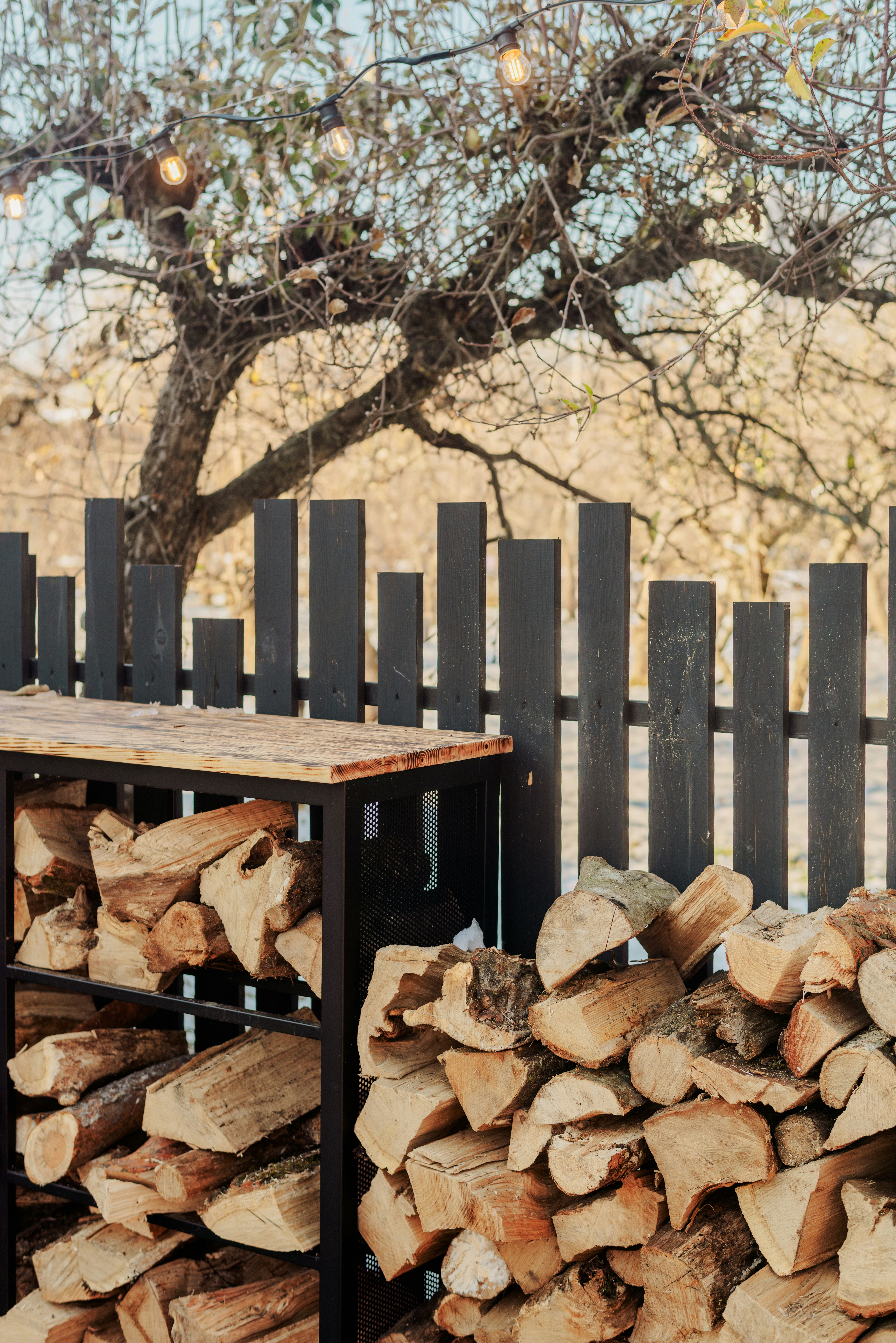 Rustic Woodpile Under String Lights: A Quiet, Textured Scene