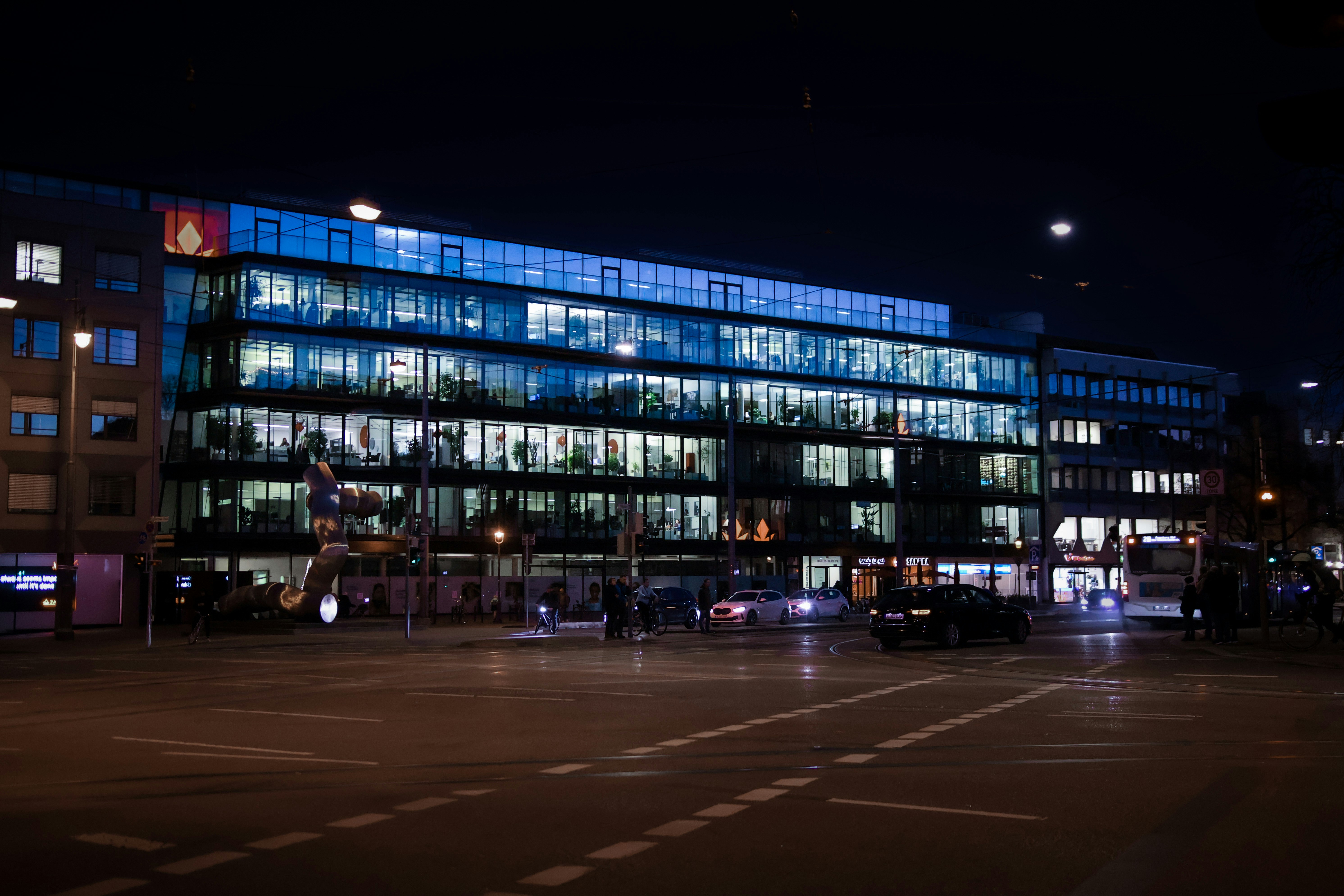 Blue-Glass Office at Night: City Lights Through a Quiet Square