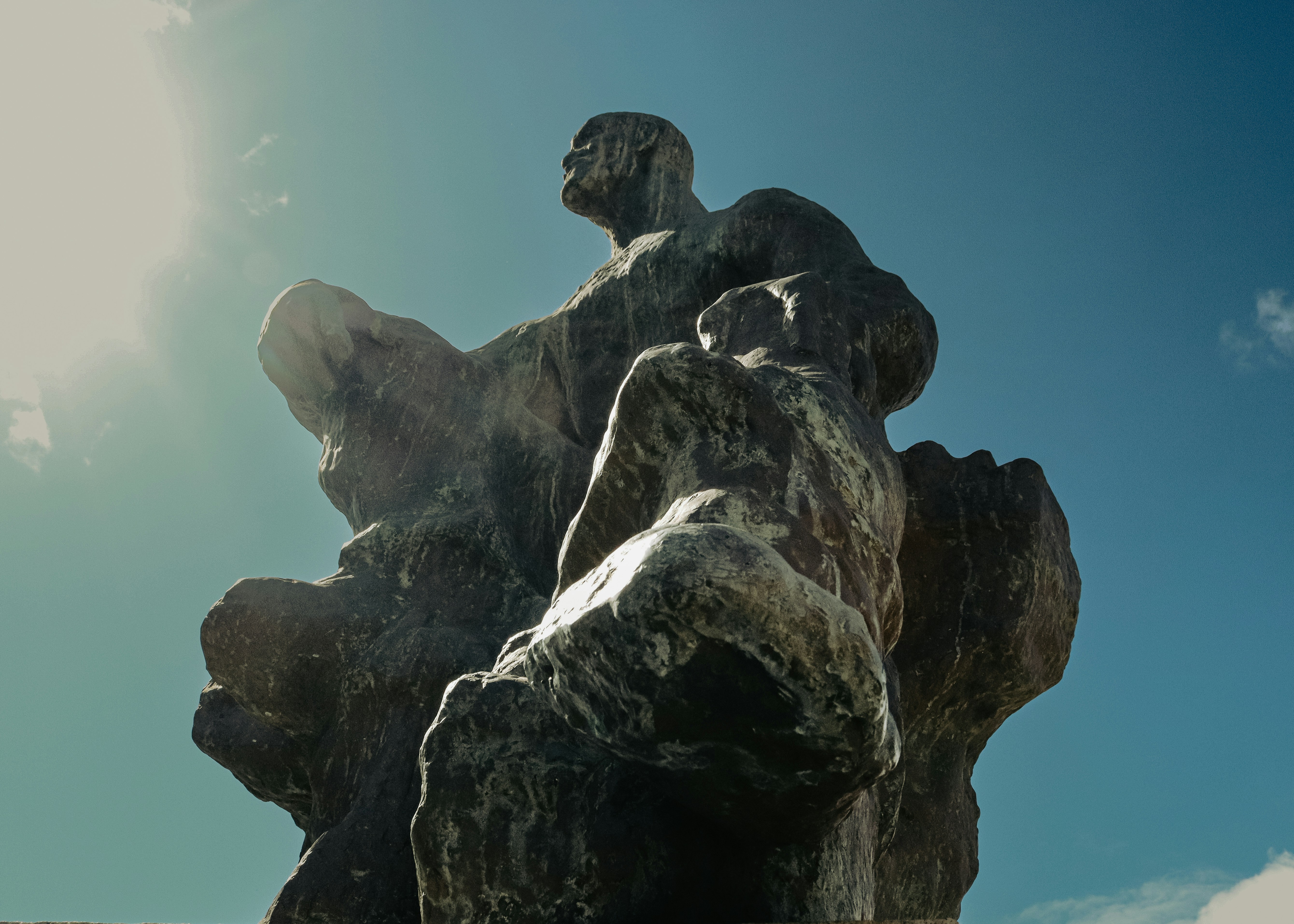 Backlit Stone Colossus: A Weathered Figure Reaching Toward the Sky