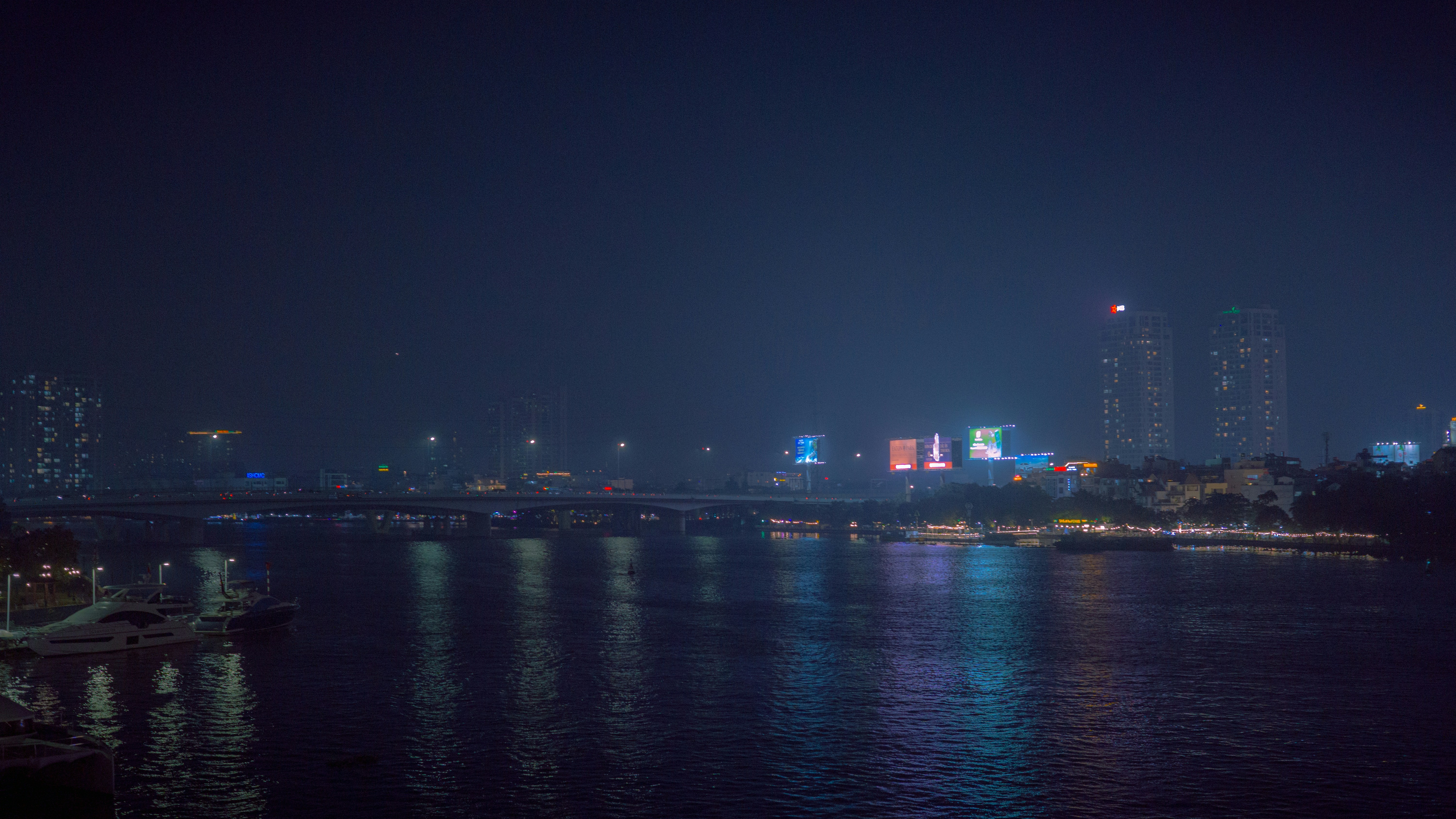 Vibrant city lights reflecting on a river at night, showcasing a blend of urban architecture and shimmering water.