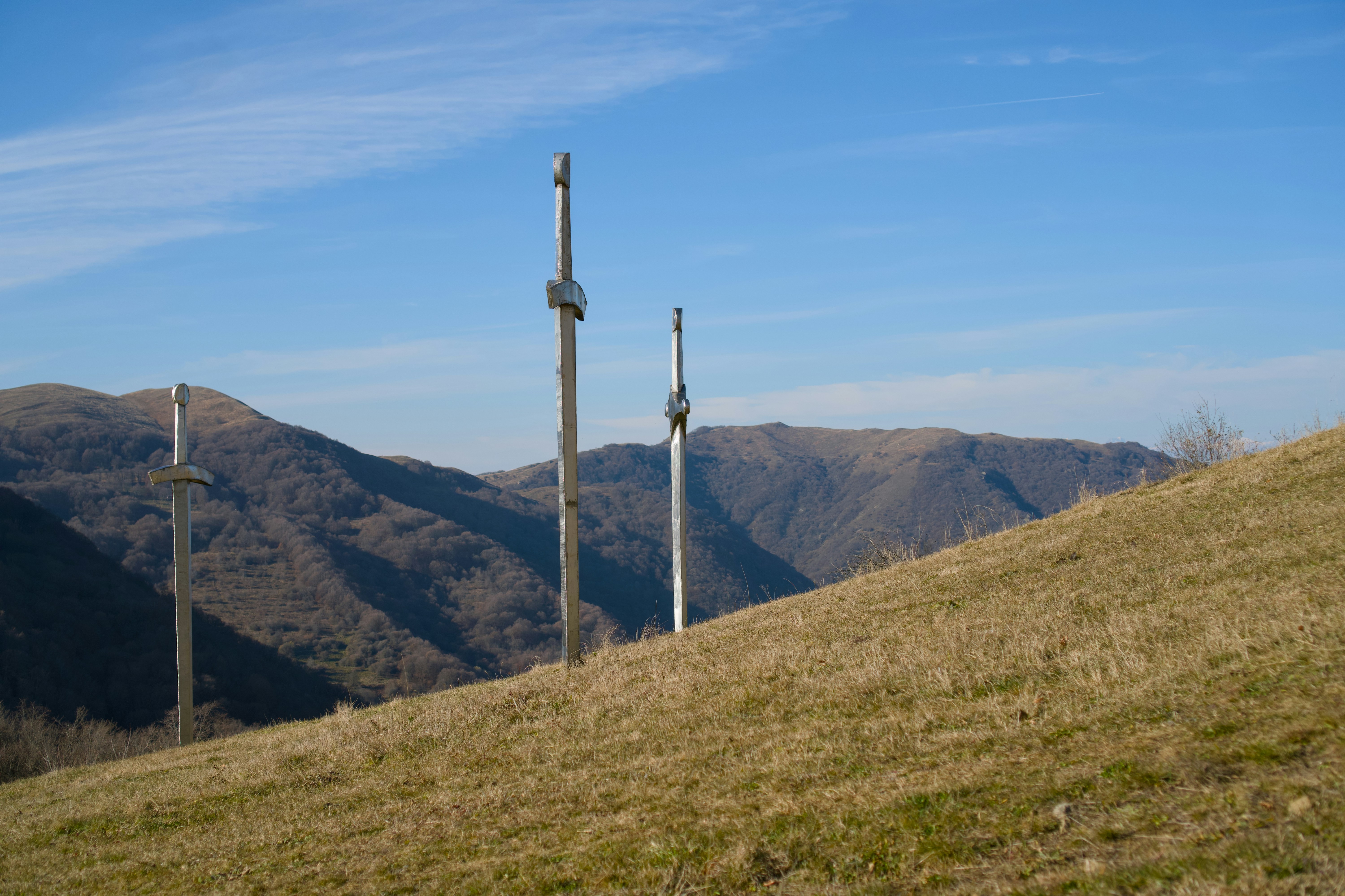 Three Weathered Poles Framing a Quiet Ridge Under a Clear Blue Sky