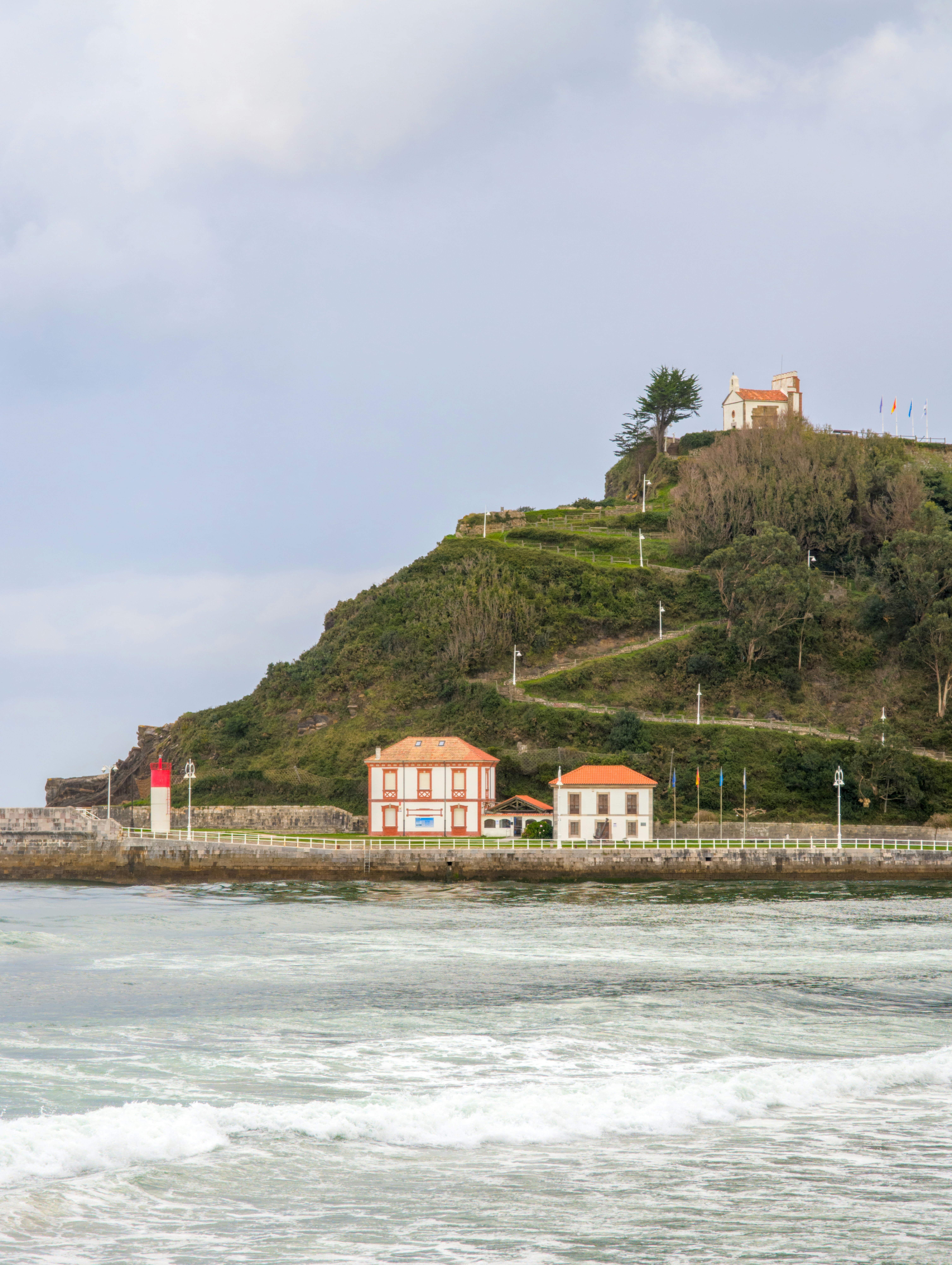 Red-Roofed Quiet Along a Green Cape Seawall