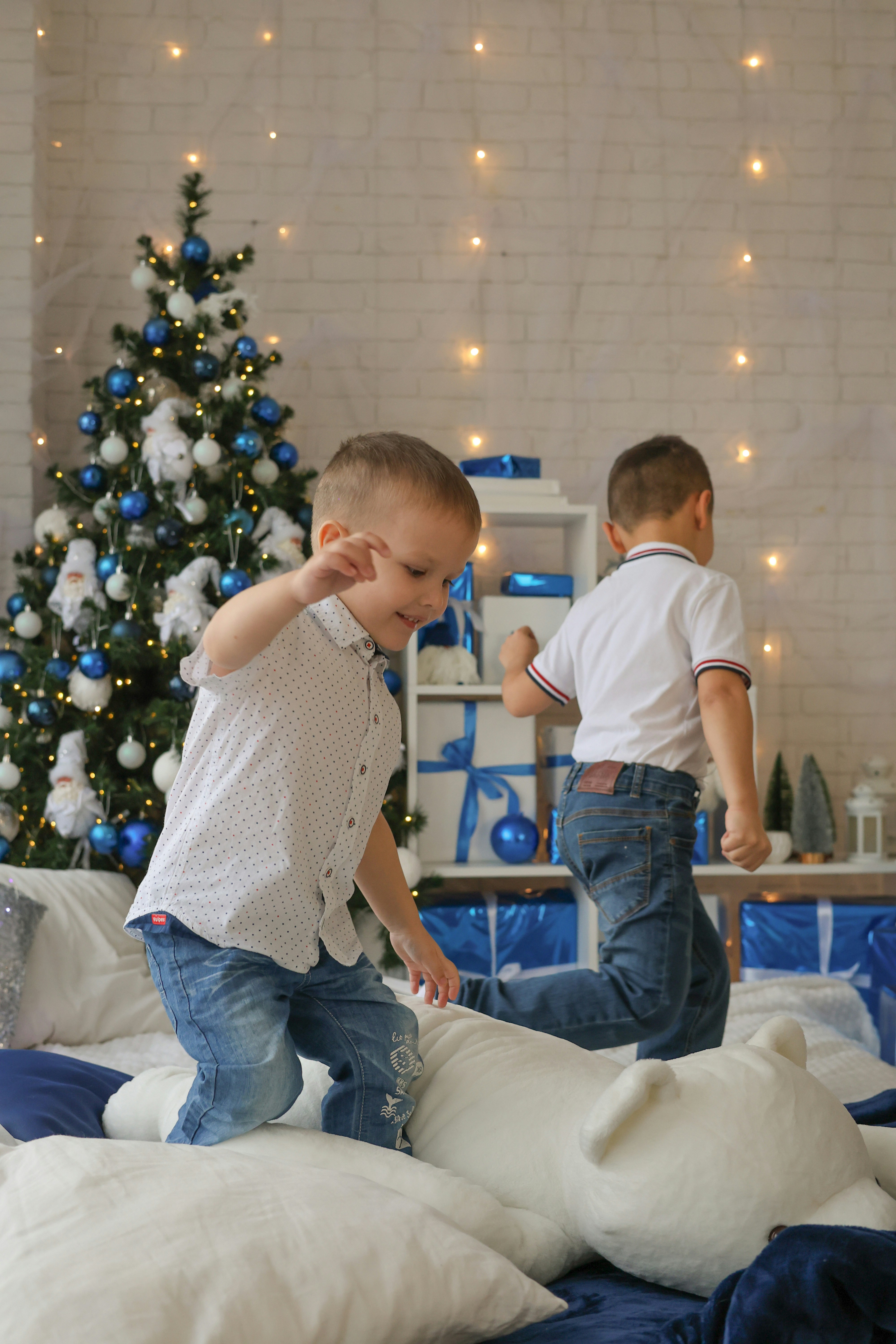 Two Kids Jumping on a Cozy Snow-White Beanbag by a Festive Tree