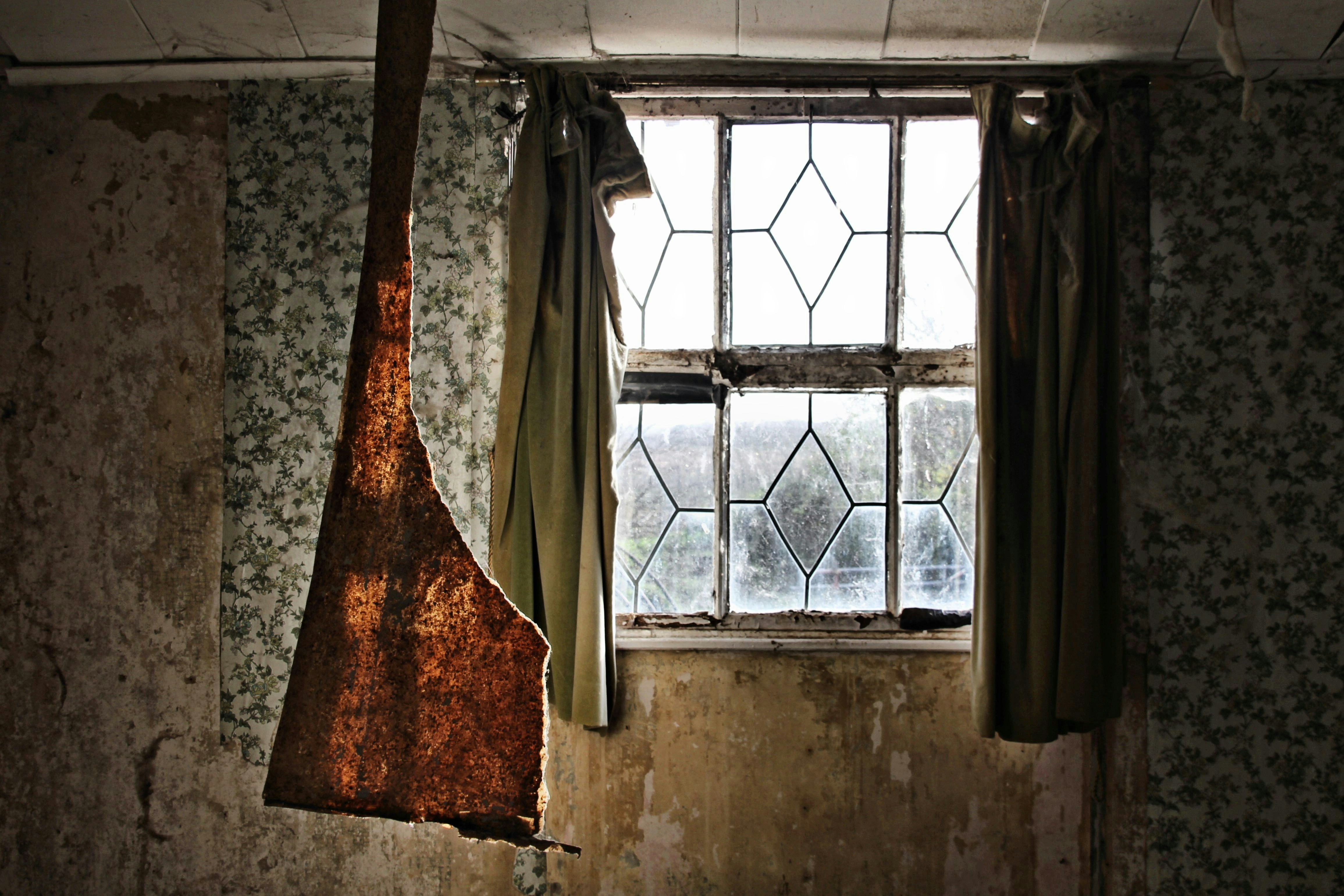 Interior of abandoned cottage with leaded windows | A room with a window and a large wooden spatula hanging from the ceiling