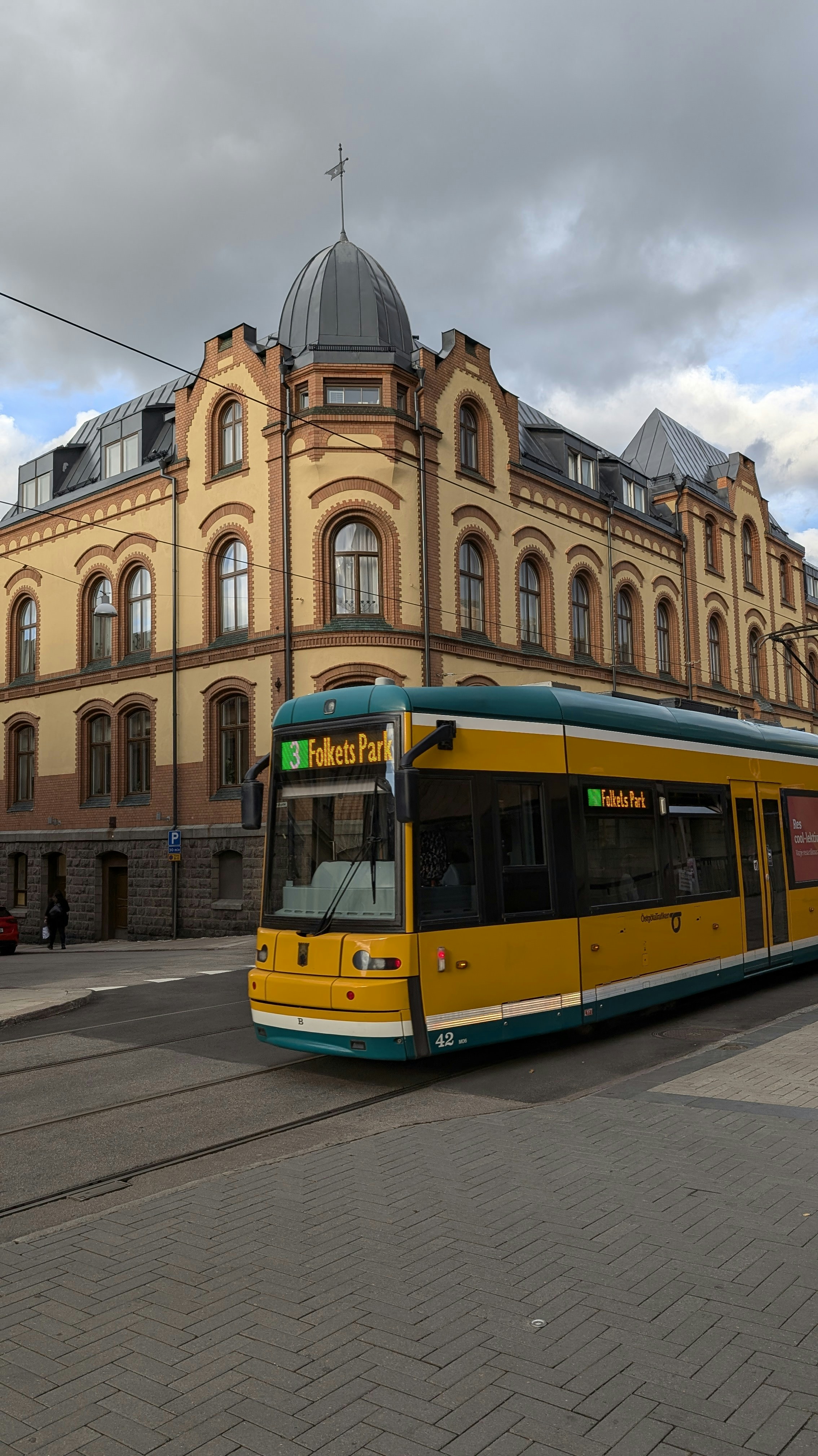 Foto Sebuah bus kuning dan hijau di jalan di sebelah sebuah gedung ...