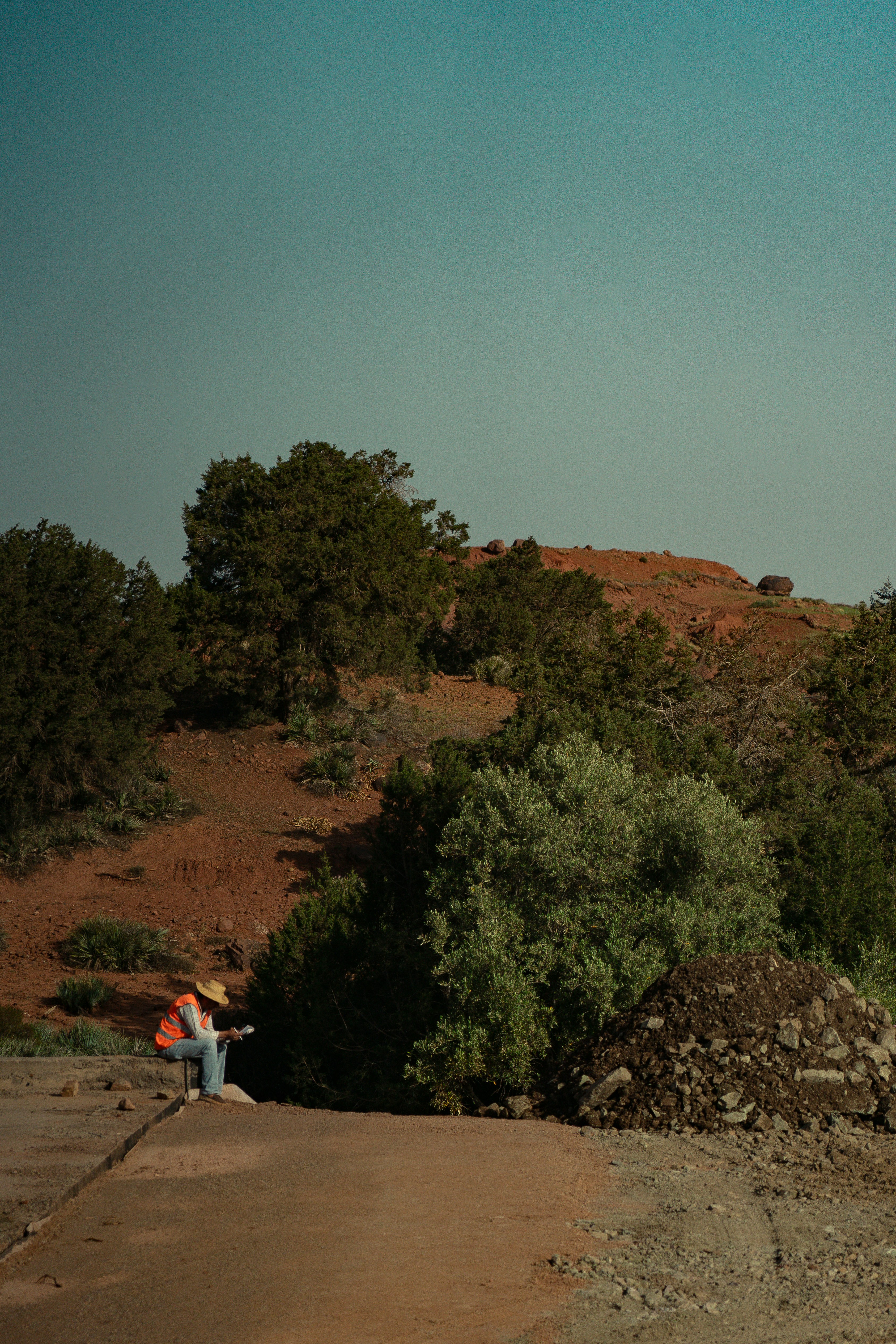 Orange Vest at the Red Ridge: A Quiet Break by the Hillside
