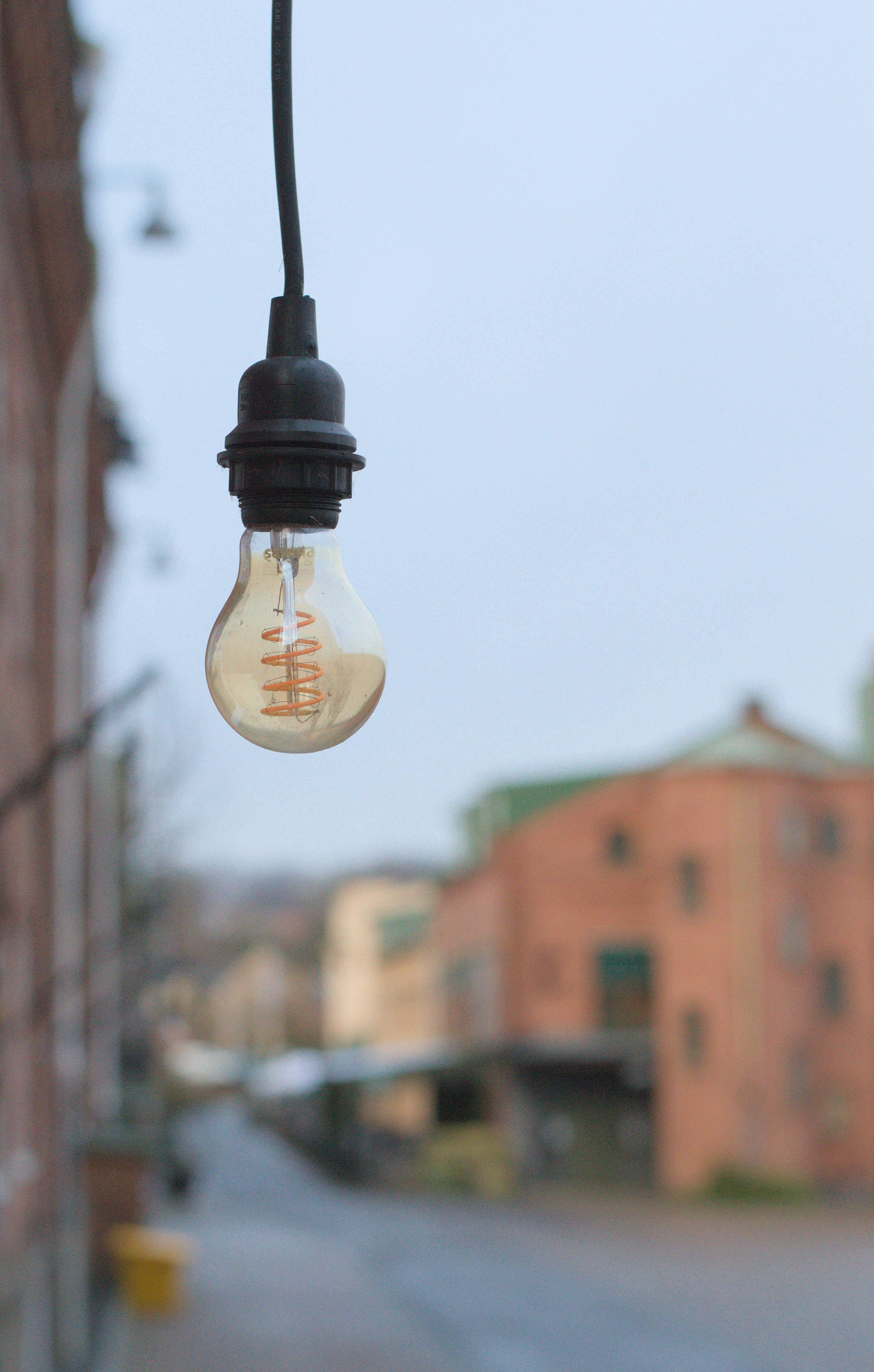 Filament in Focus: A Lone Edison Bulb Framing a Quiet Brick Street