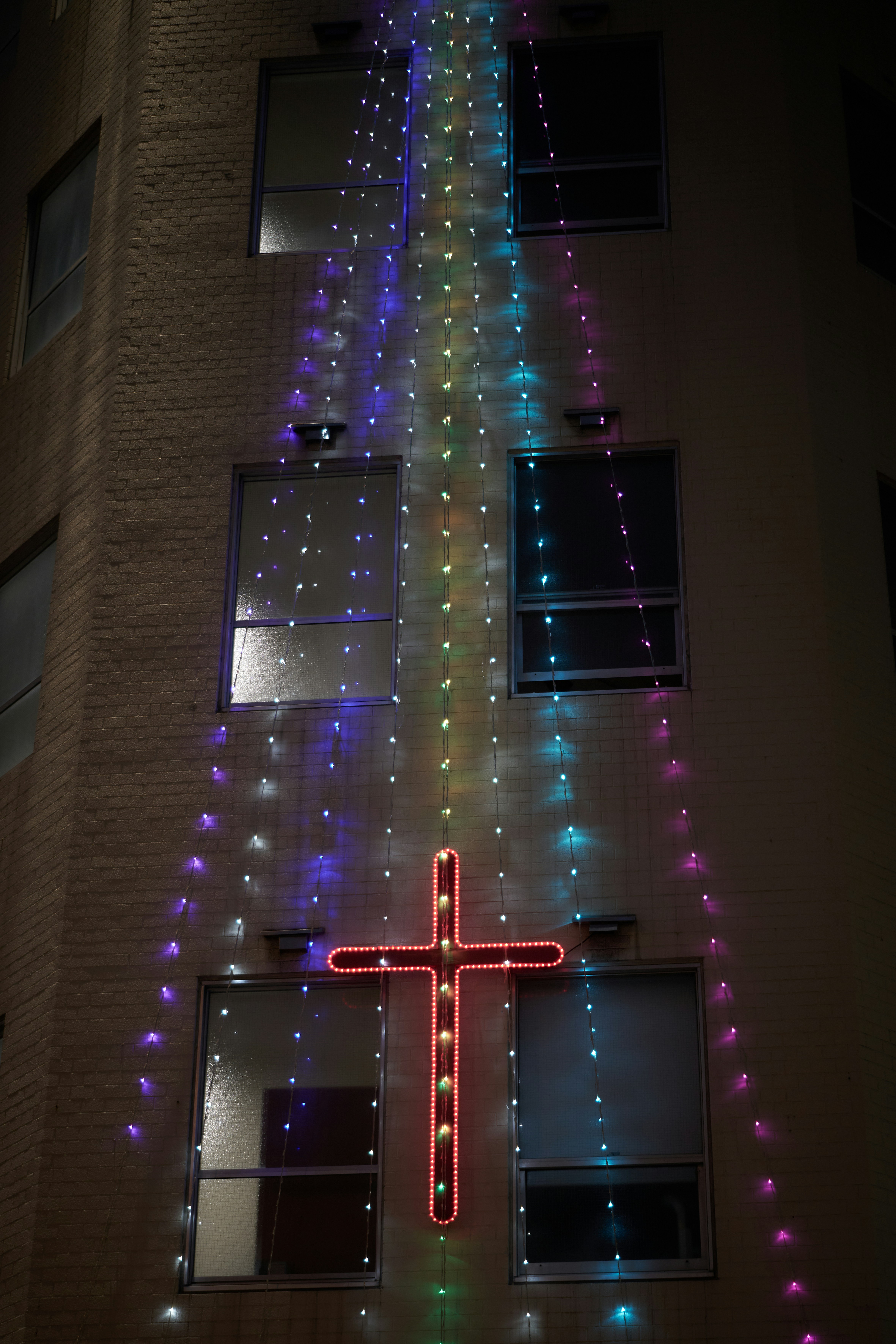 A lighted cross on the side of a building photo – Free Religious cross ...