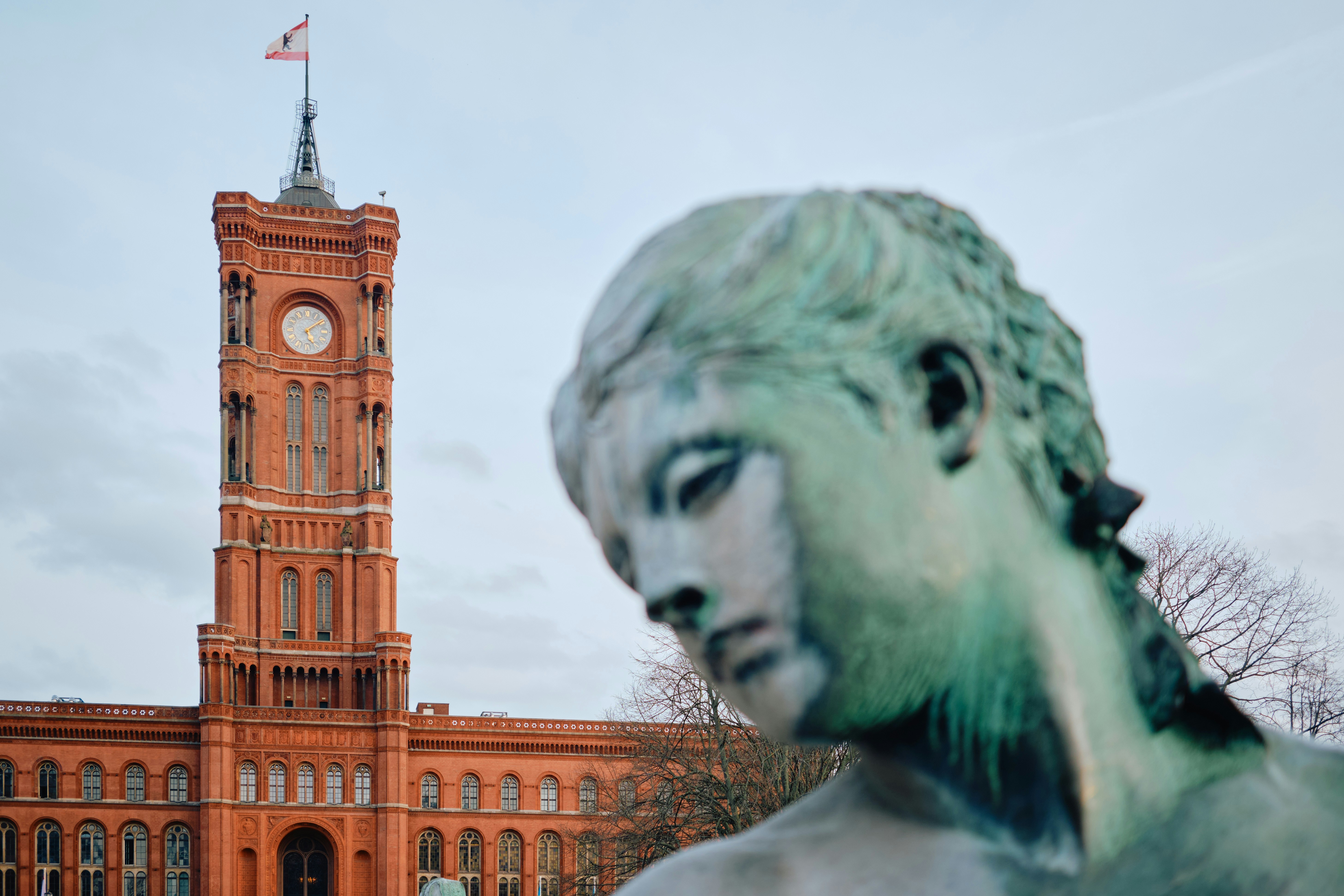 A statue in front of a building with a clock towerAlireza Banijani