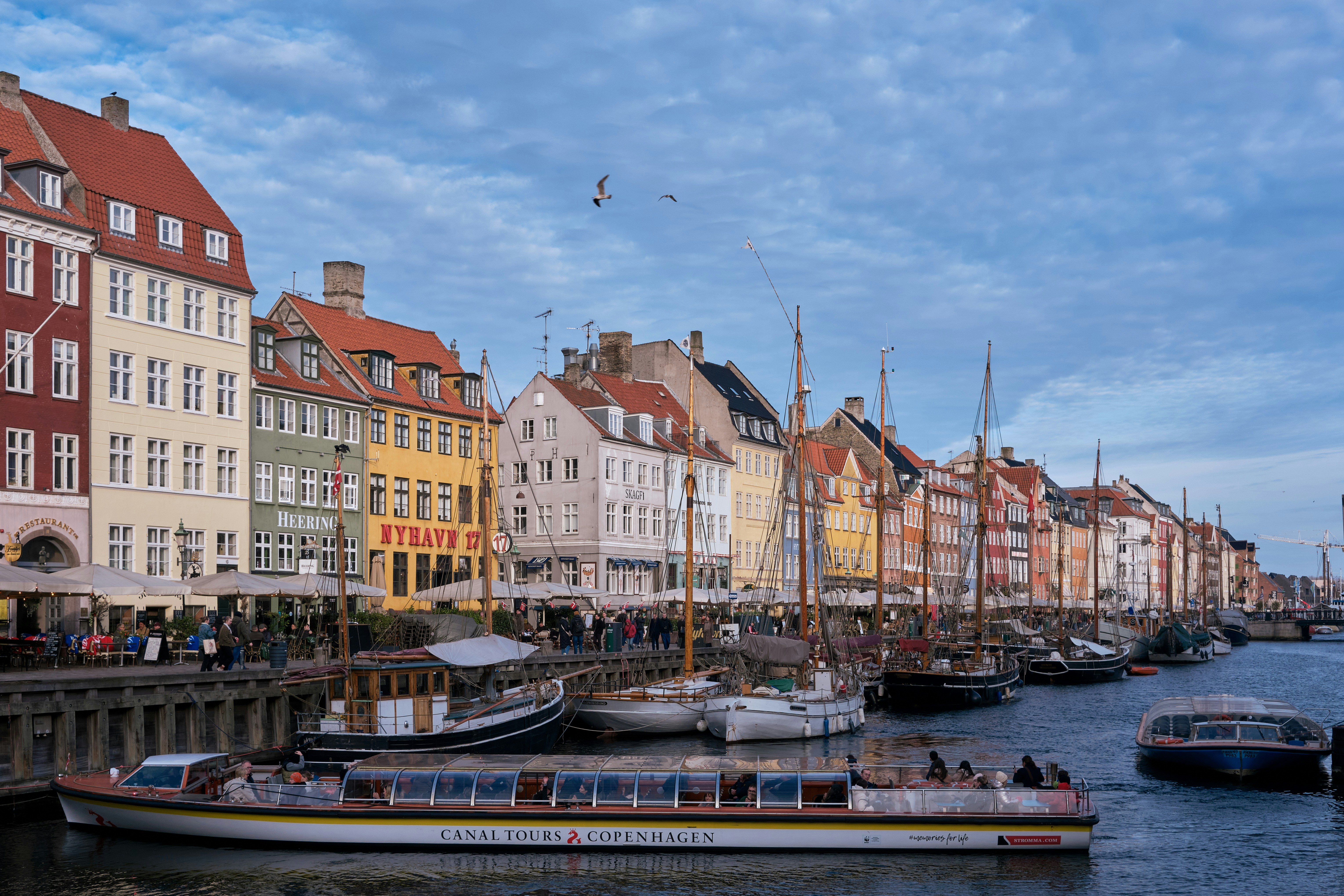 Colorful buildings line a bustling canal with boats in Copenhagen.