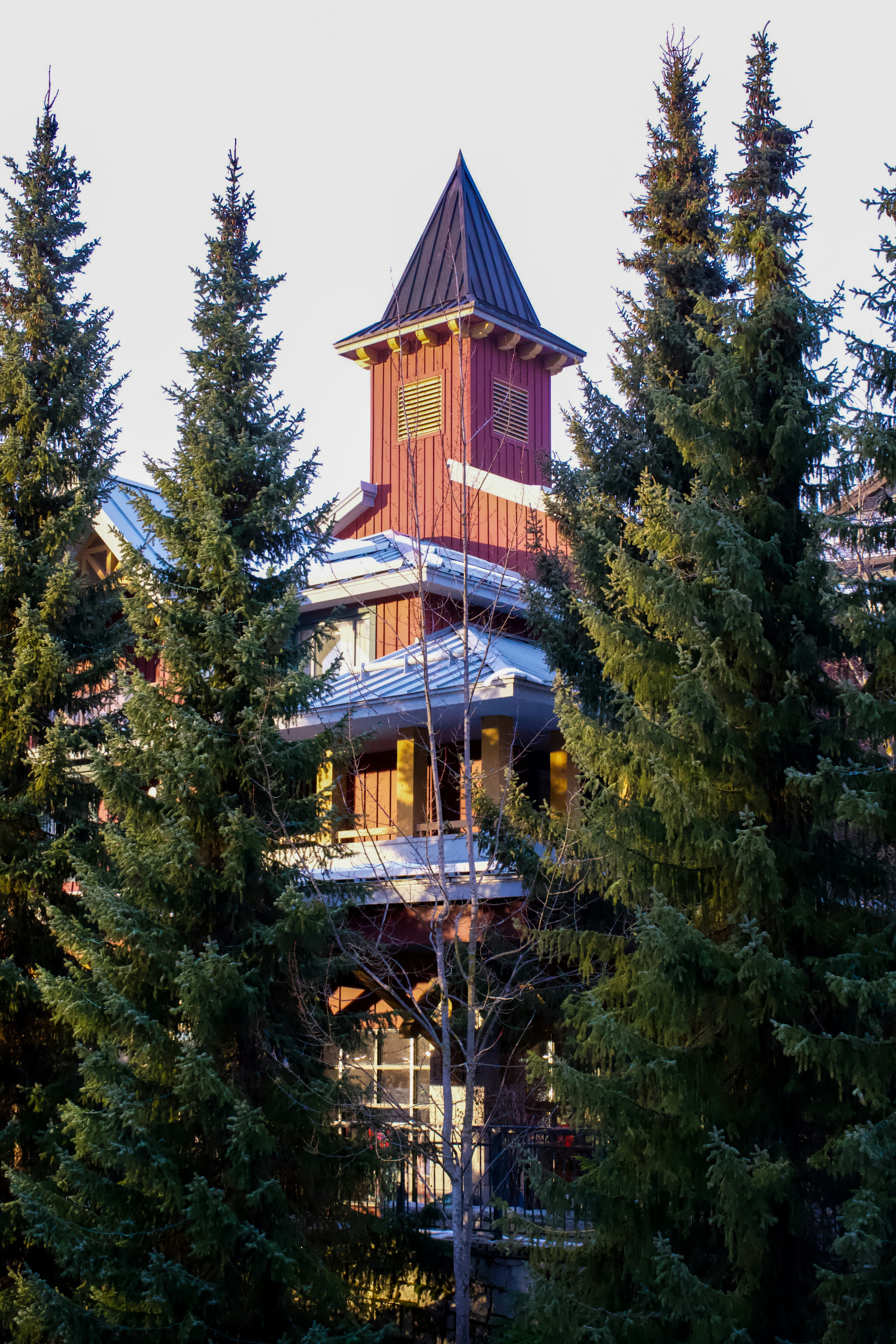Snowlit lodge tower rising through evergreen sentinels