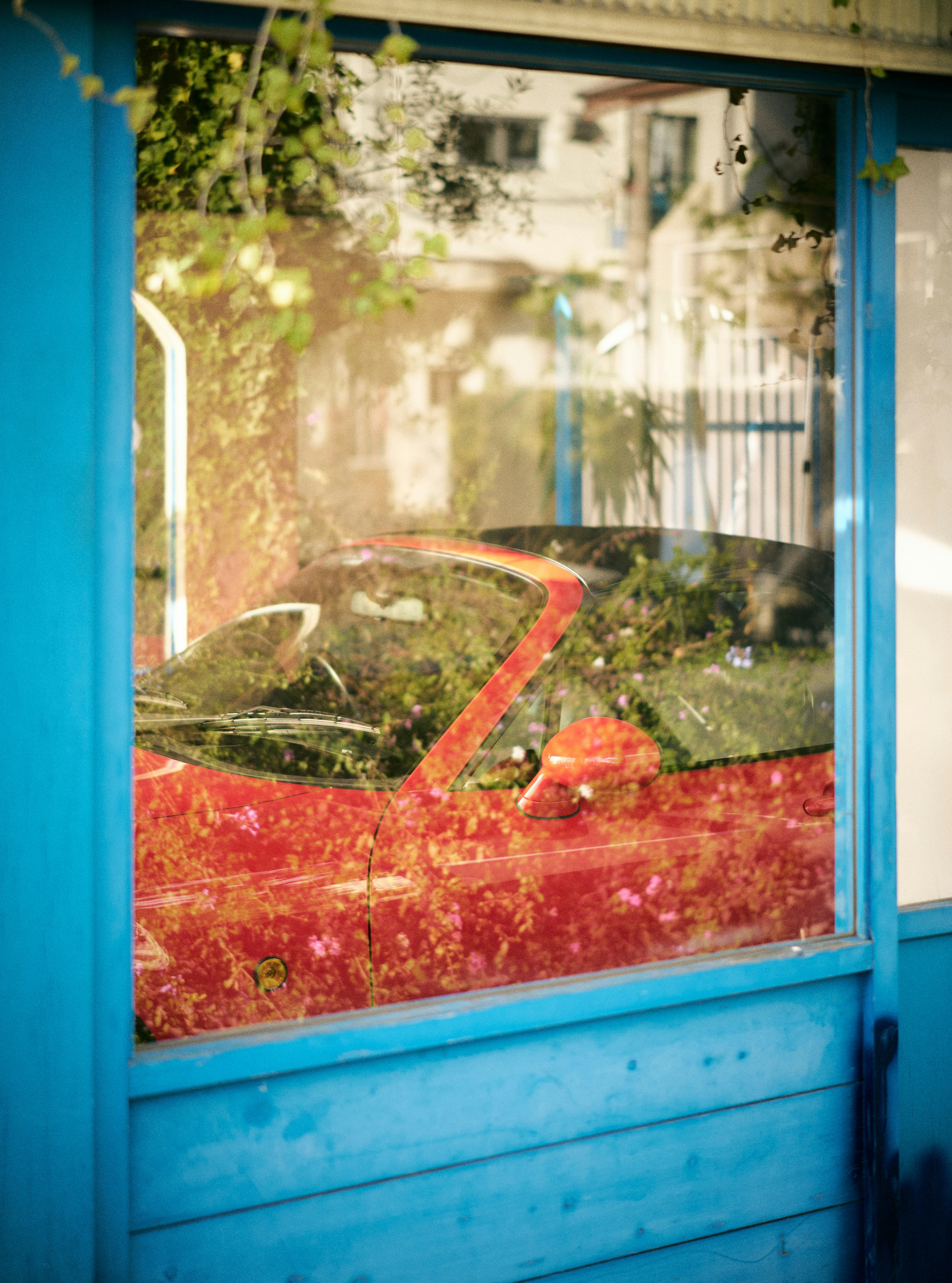 Blue Frame, Red Convertible: A Hidden View Through the Window