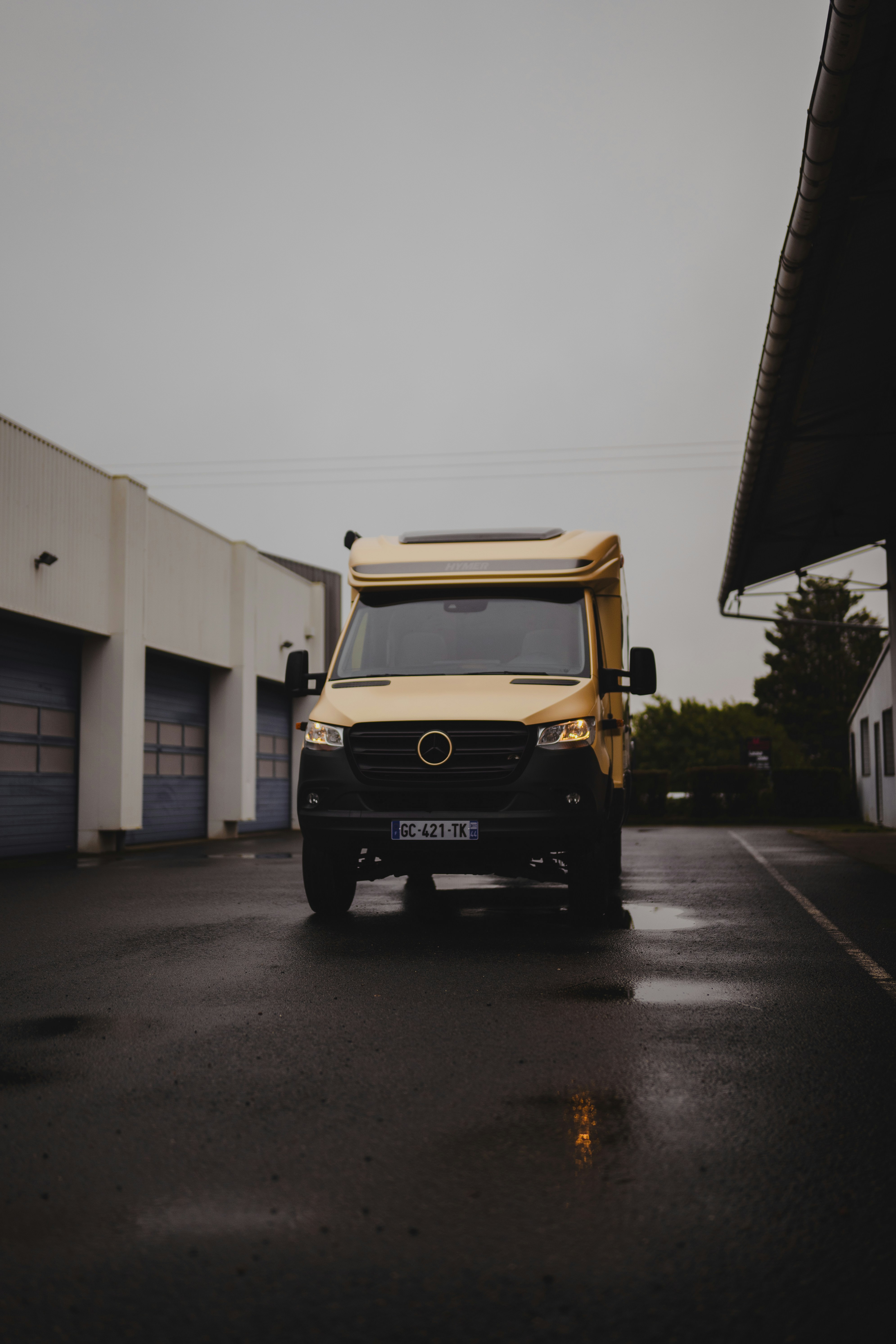 Amber Delivery Van Anchoring a Rain-Washed Industrial Yard