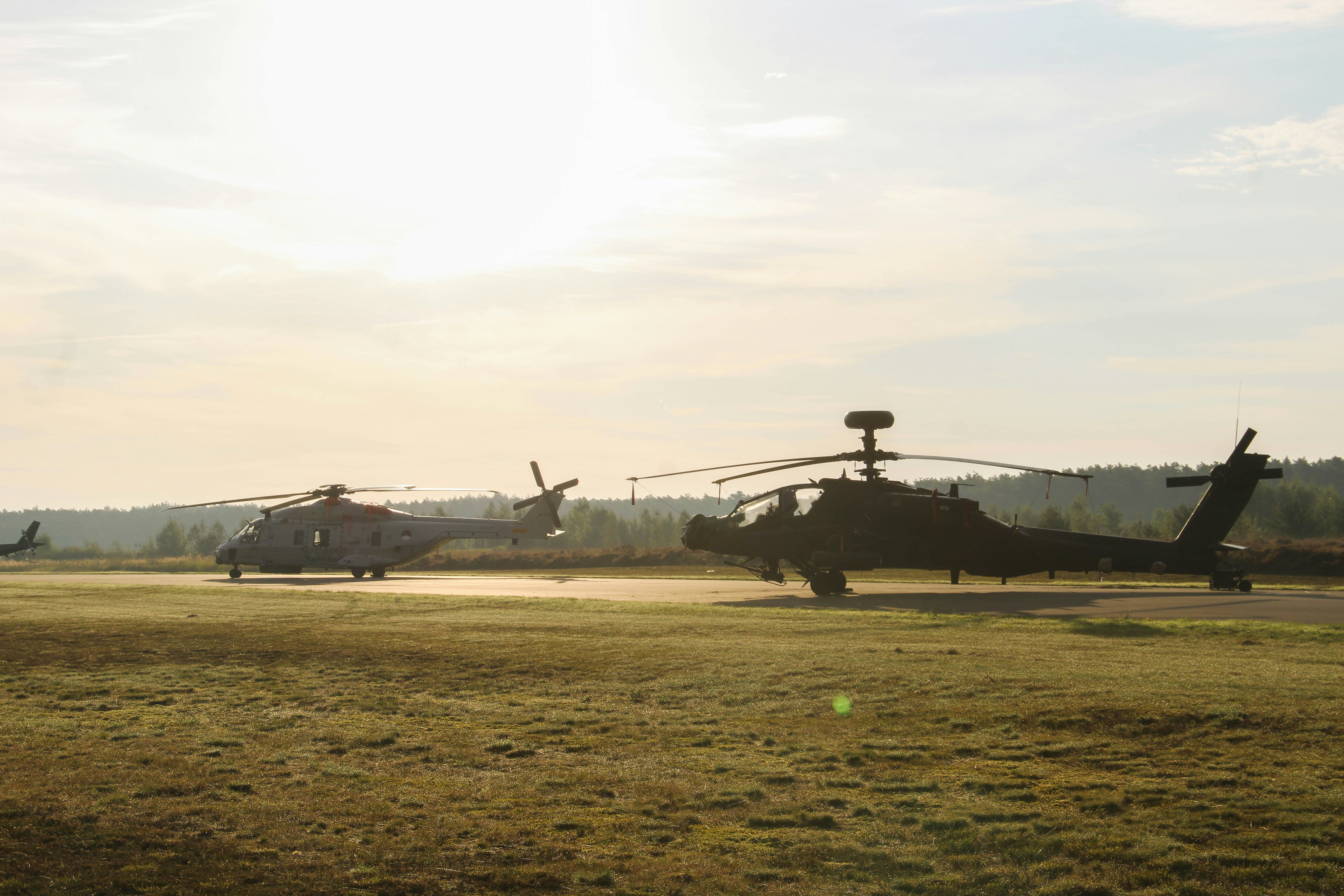 A group of military helicopters sitting on top of a field photo – Free ...