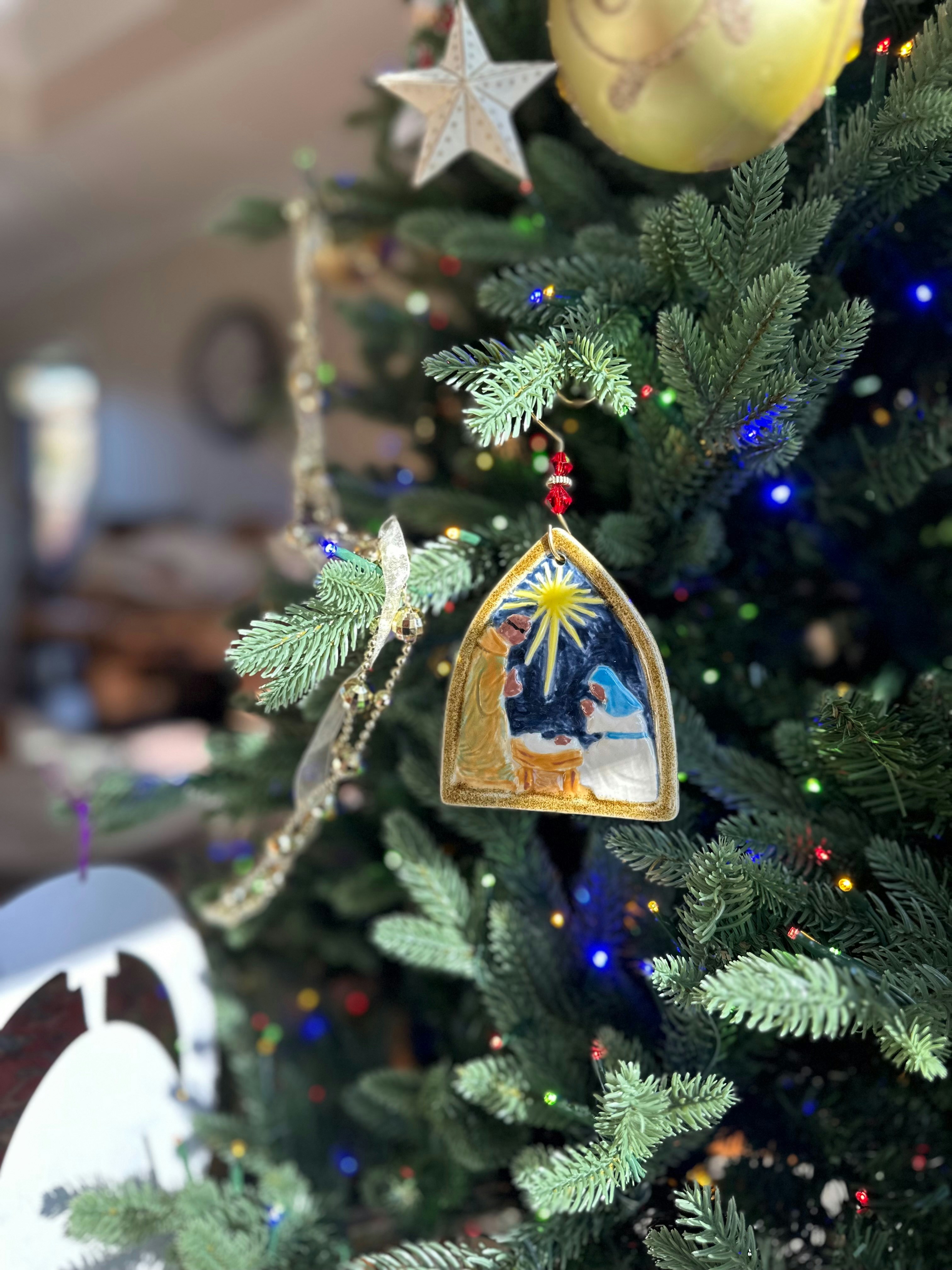 Gold Nativity Pendant Adorns a Twinkling Christmas Tree