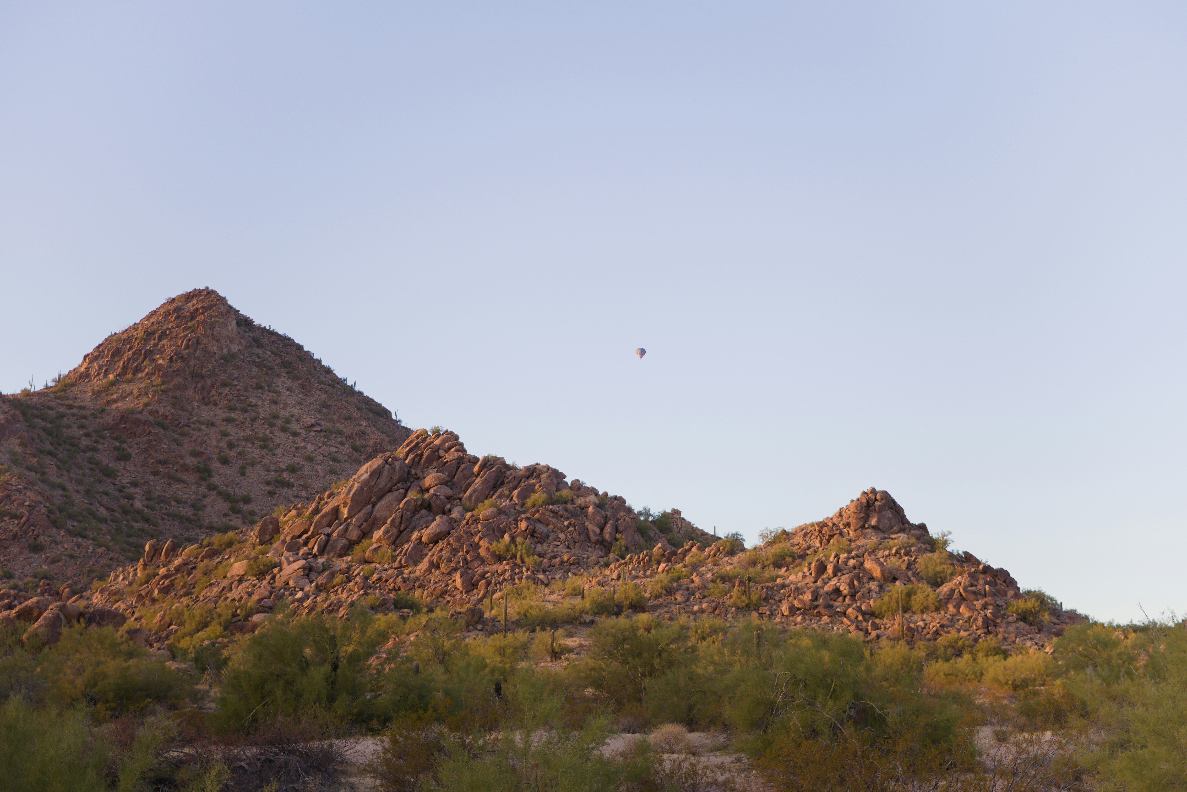 Balloon Over Granite: A Quiet Desert Horizon Under Clear Skies