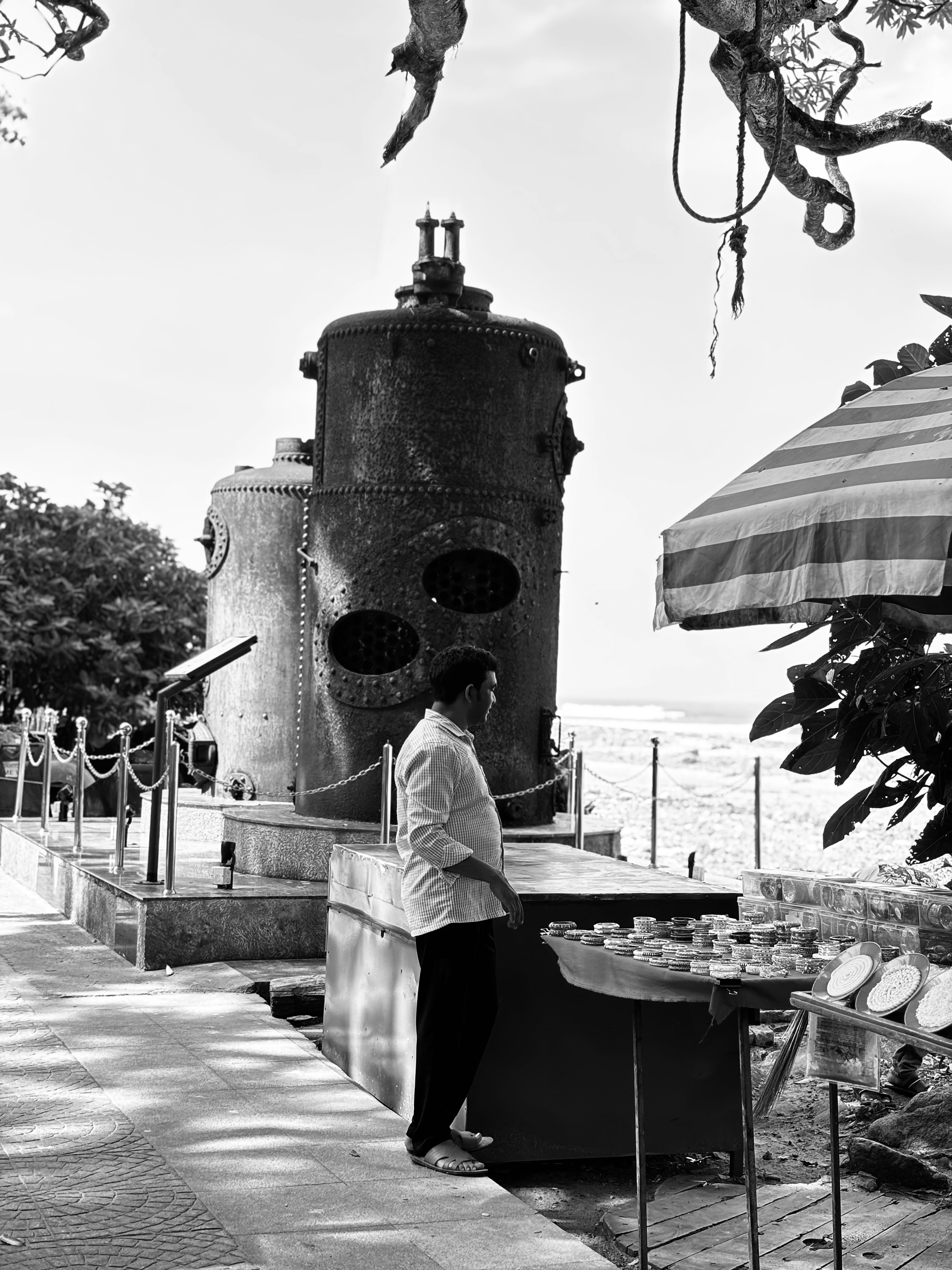 Tide and Iron: A Seaside Market Stance by a Rusted Industrial Tank