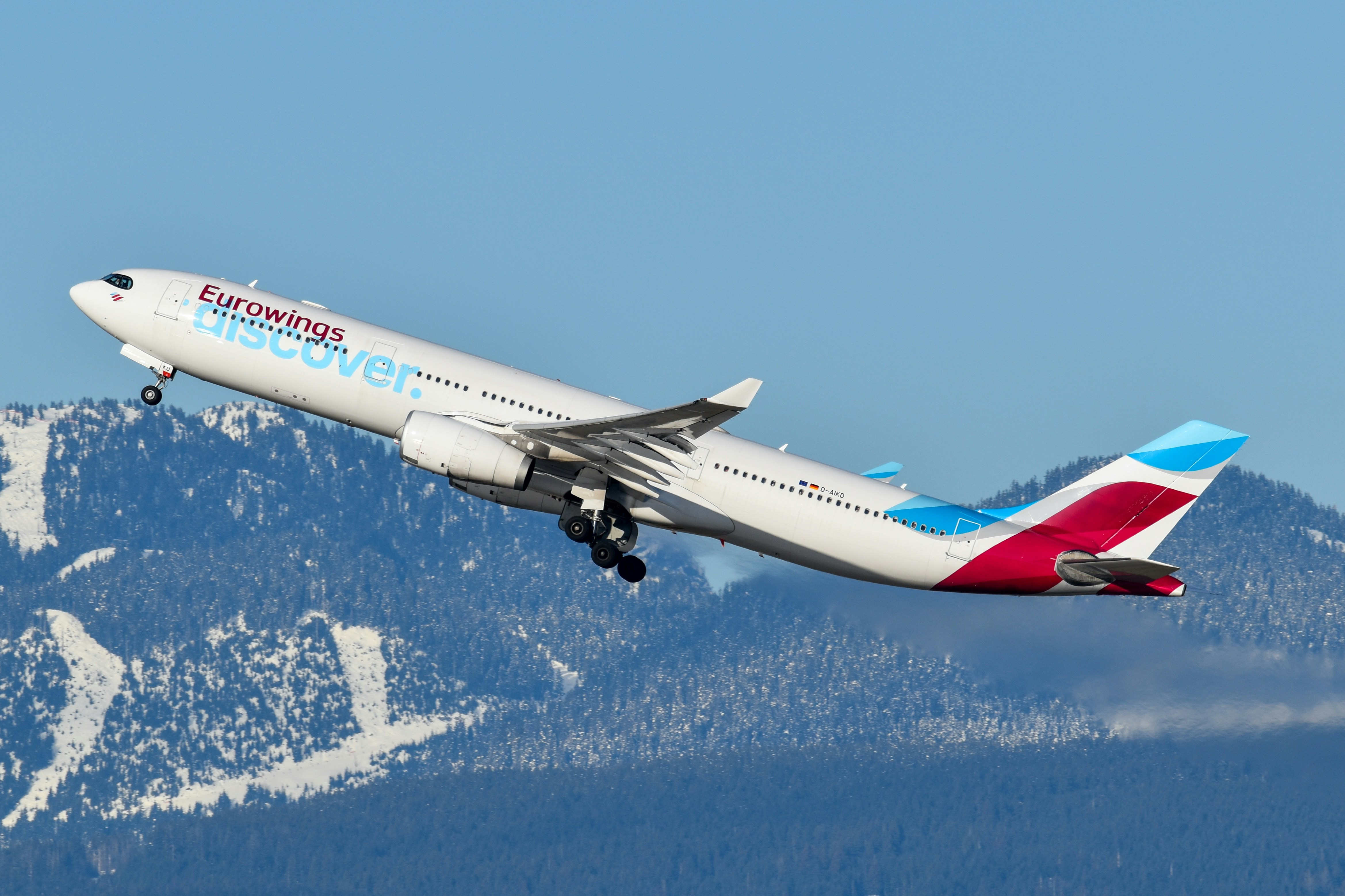 A large passenger jet flying over a mountain range photo – Free ...