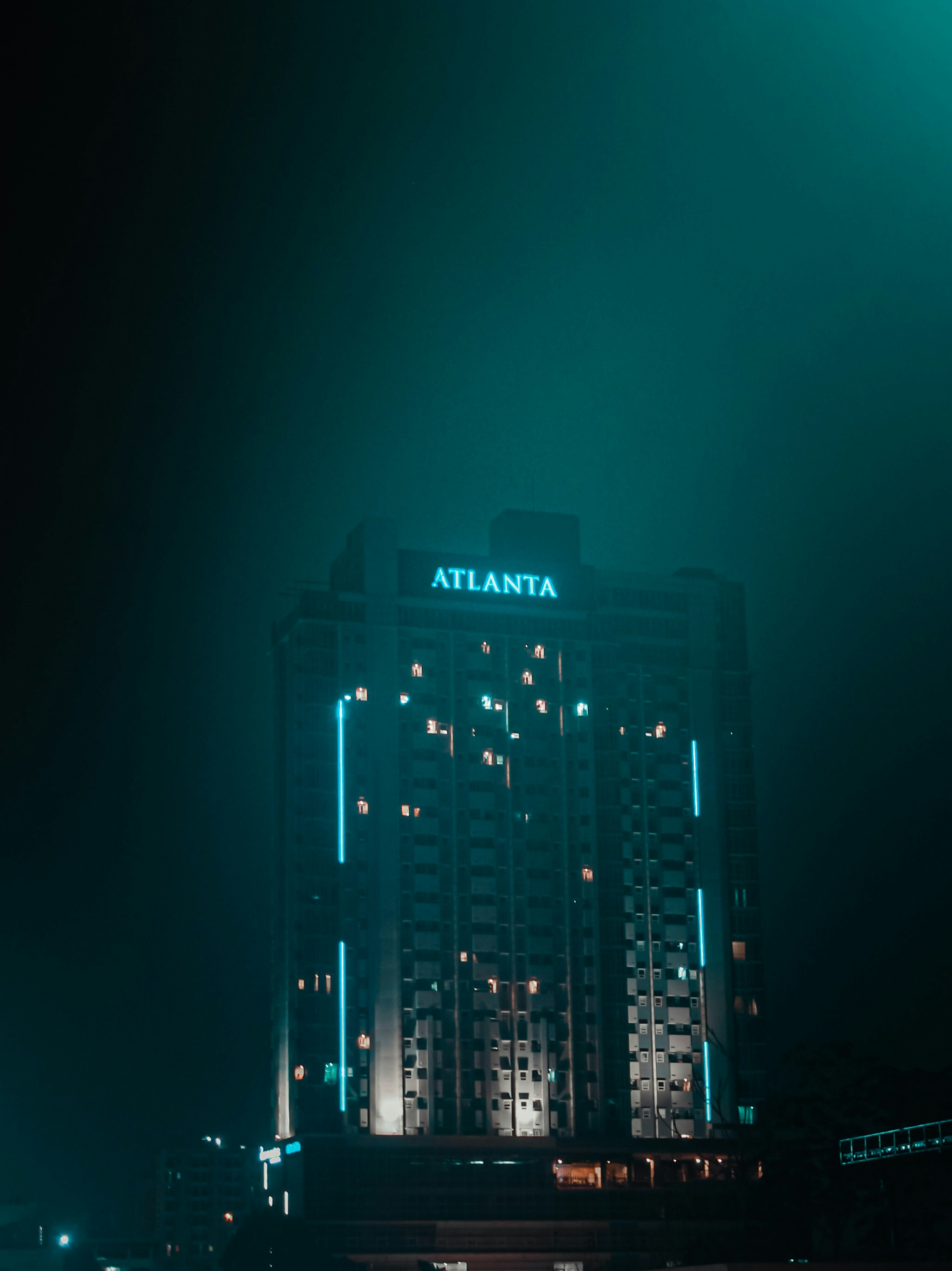 Illuminated high-rise building in Atlanta, showcasing a neon glow against a moody night sky.