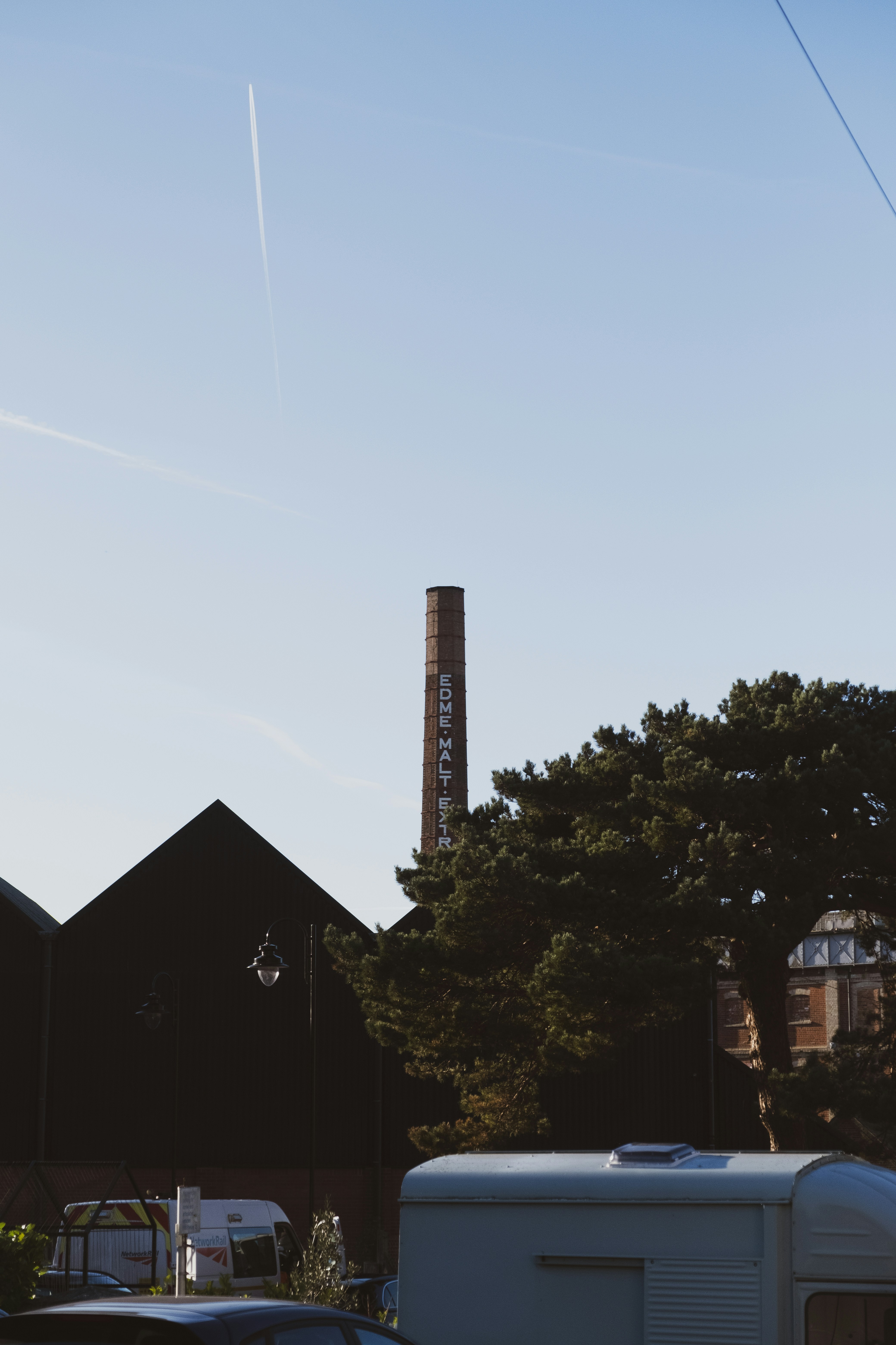 Brick Chimney Silhouette: Pines, Caravan, Under a Quiet Blue Sky