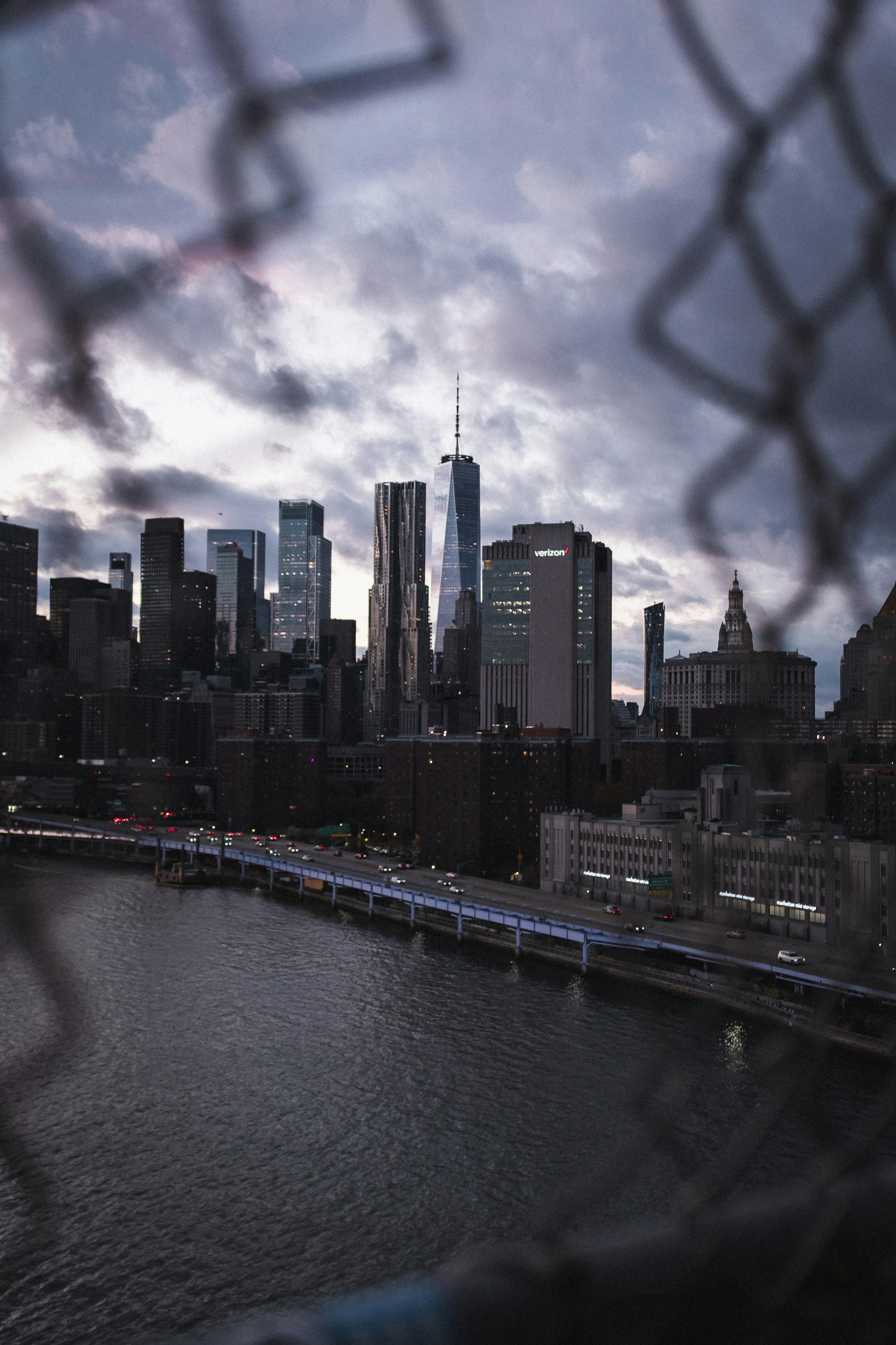 A view of a city skyline through a chain link fence photo – Free Car ...