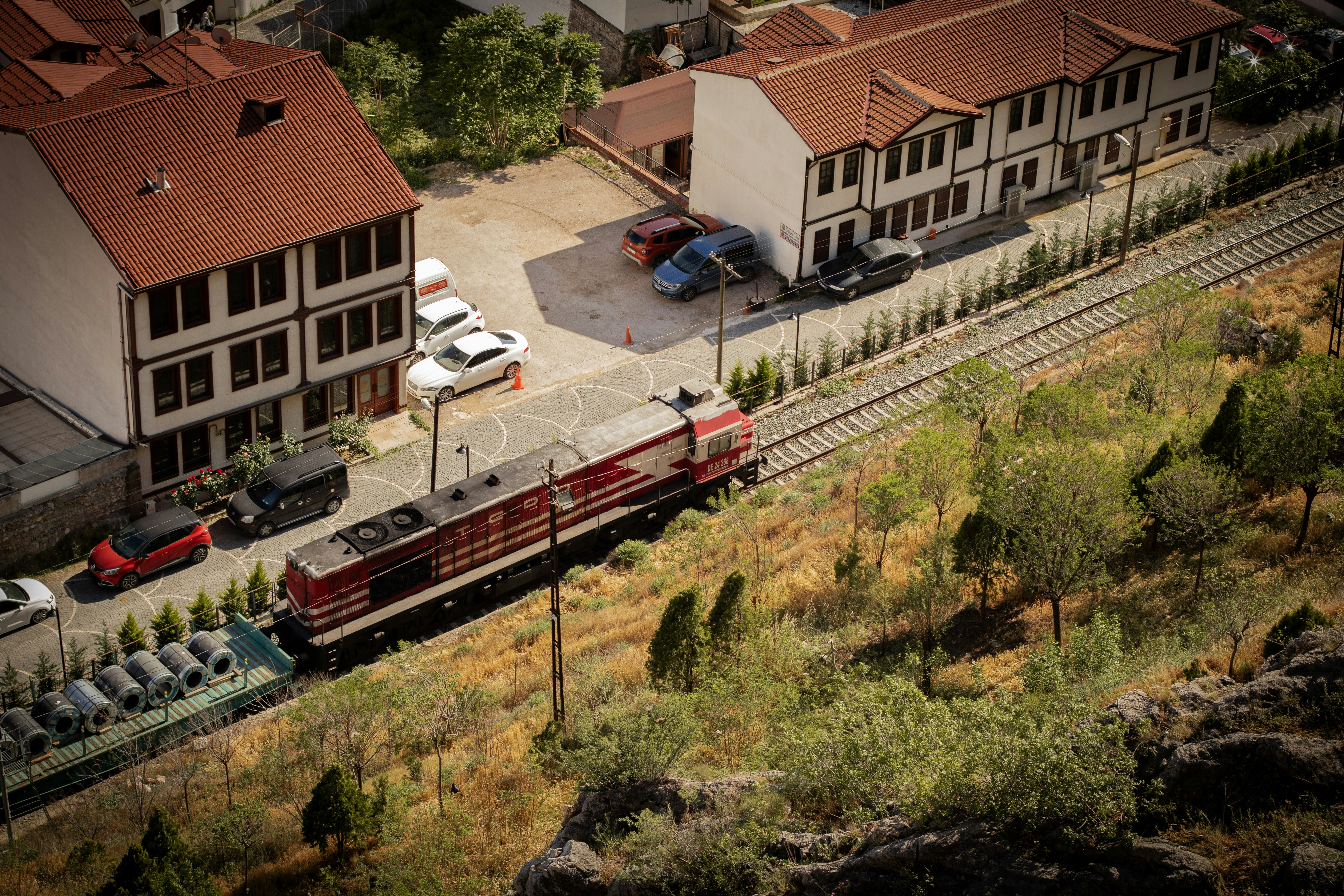 Red Locomotive Winding Through a Sunlit Hillside Town
