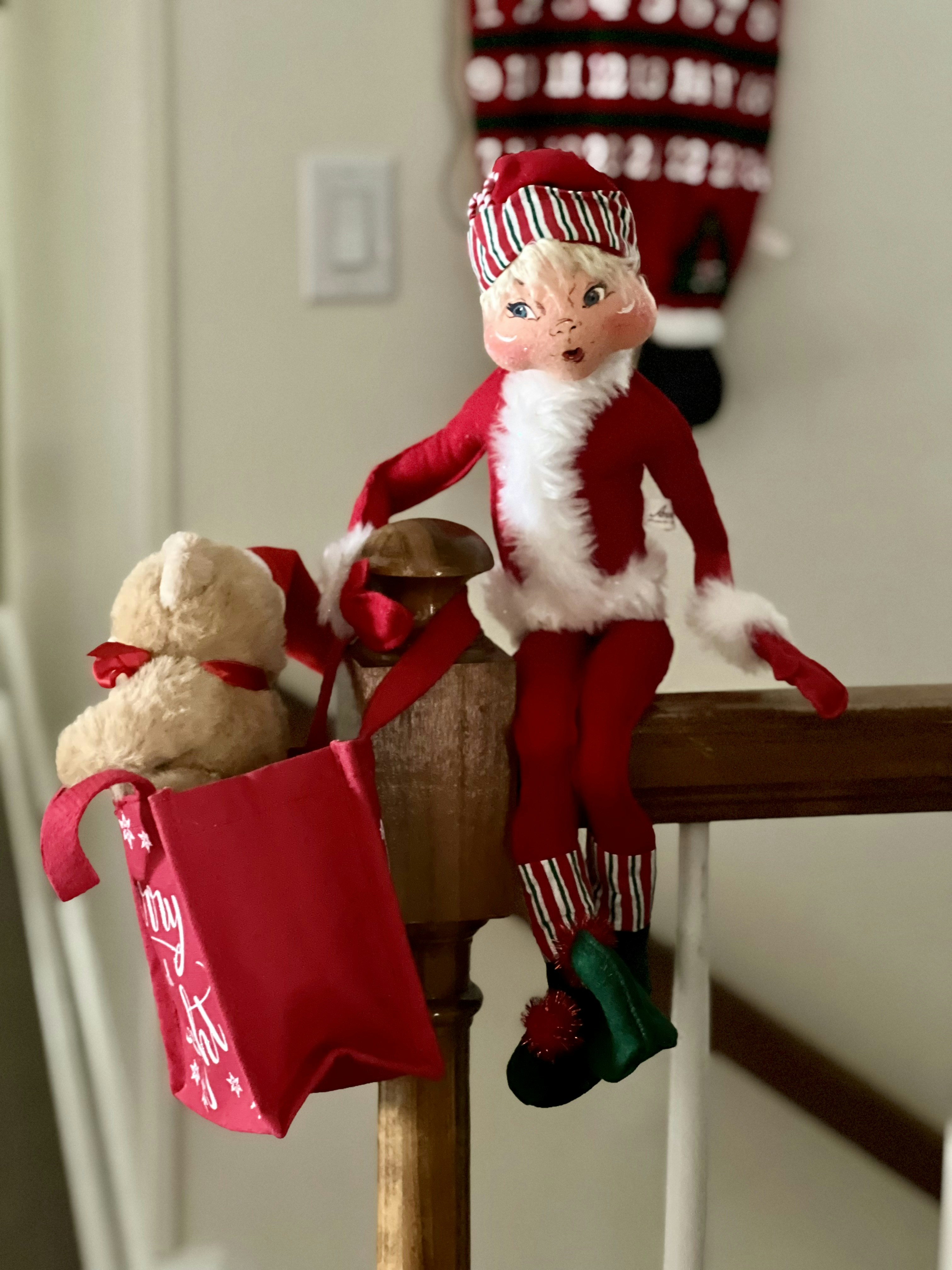 Banister Scout: Red-Suited Elf Guards a Holiday Tote