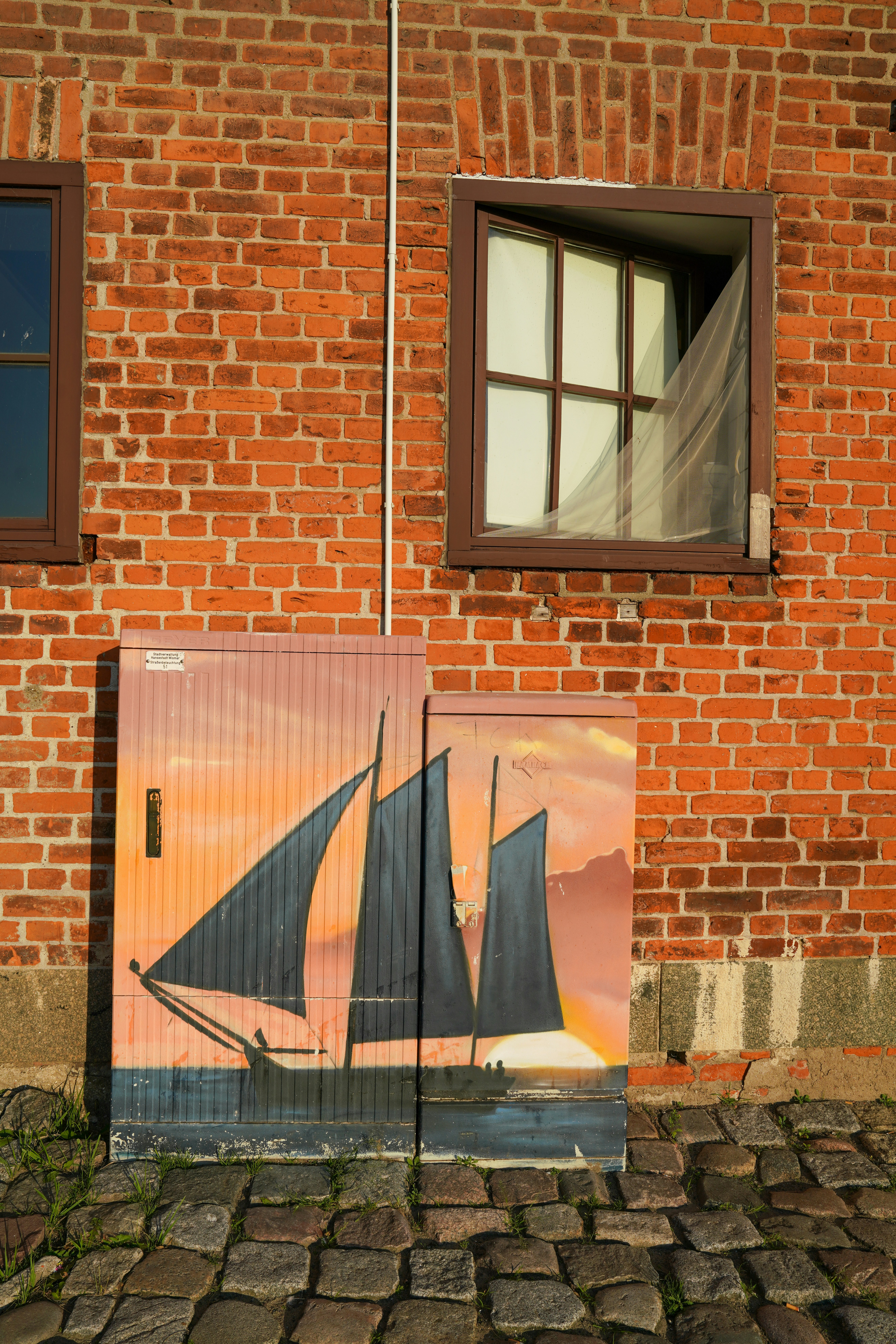 Sails at Dusk: A Painted Panel Anchored to a Brick Facade