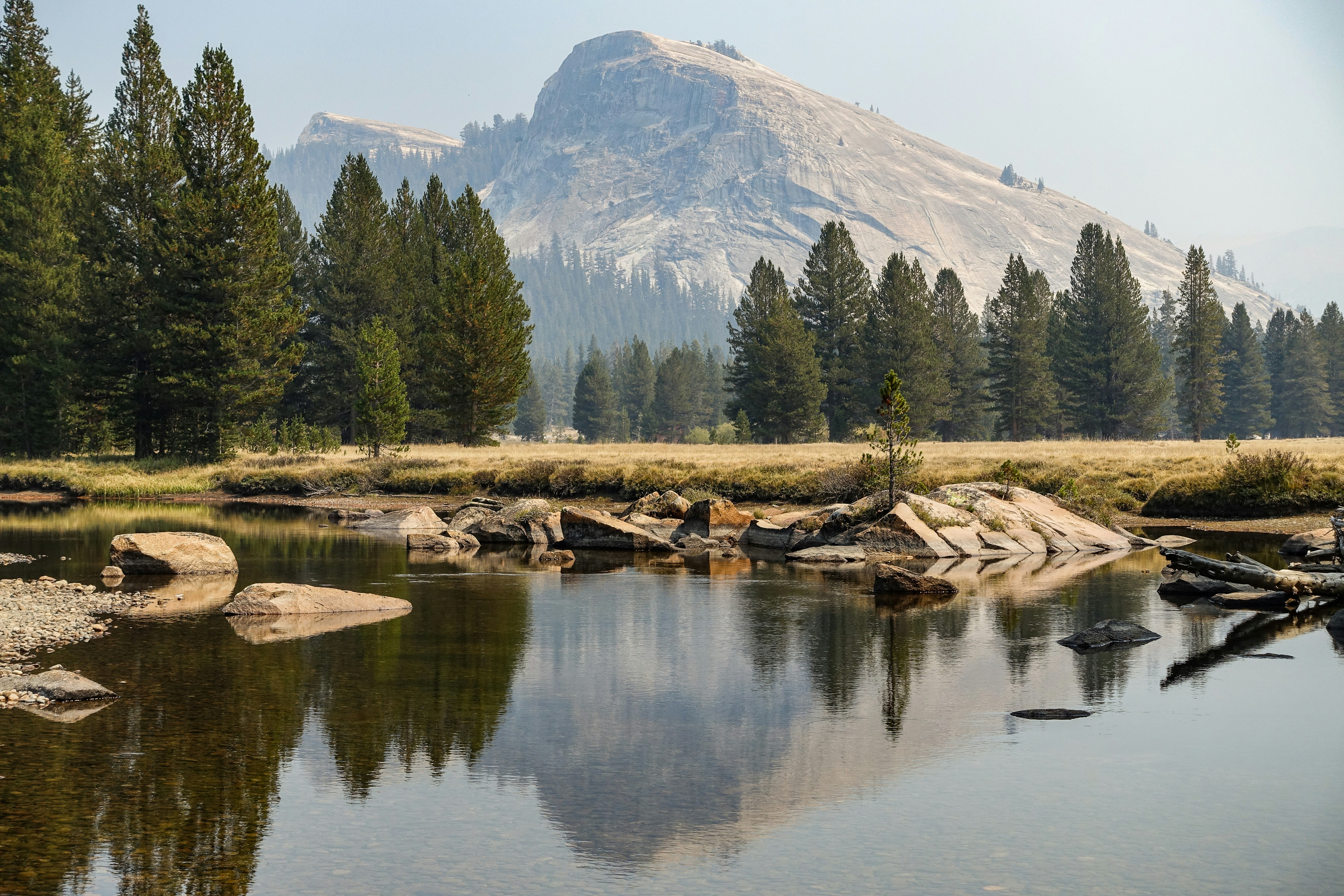 A mountain is reflected in the still water of a stream