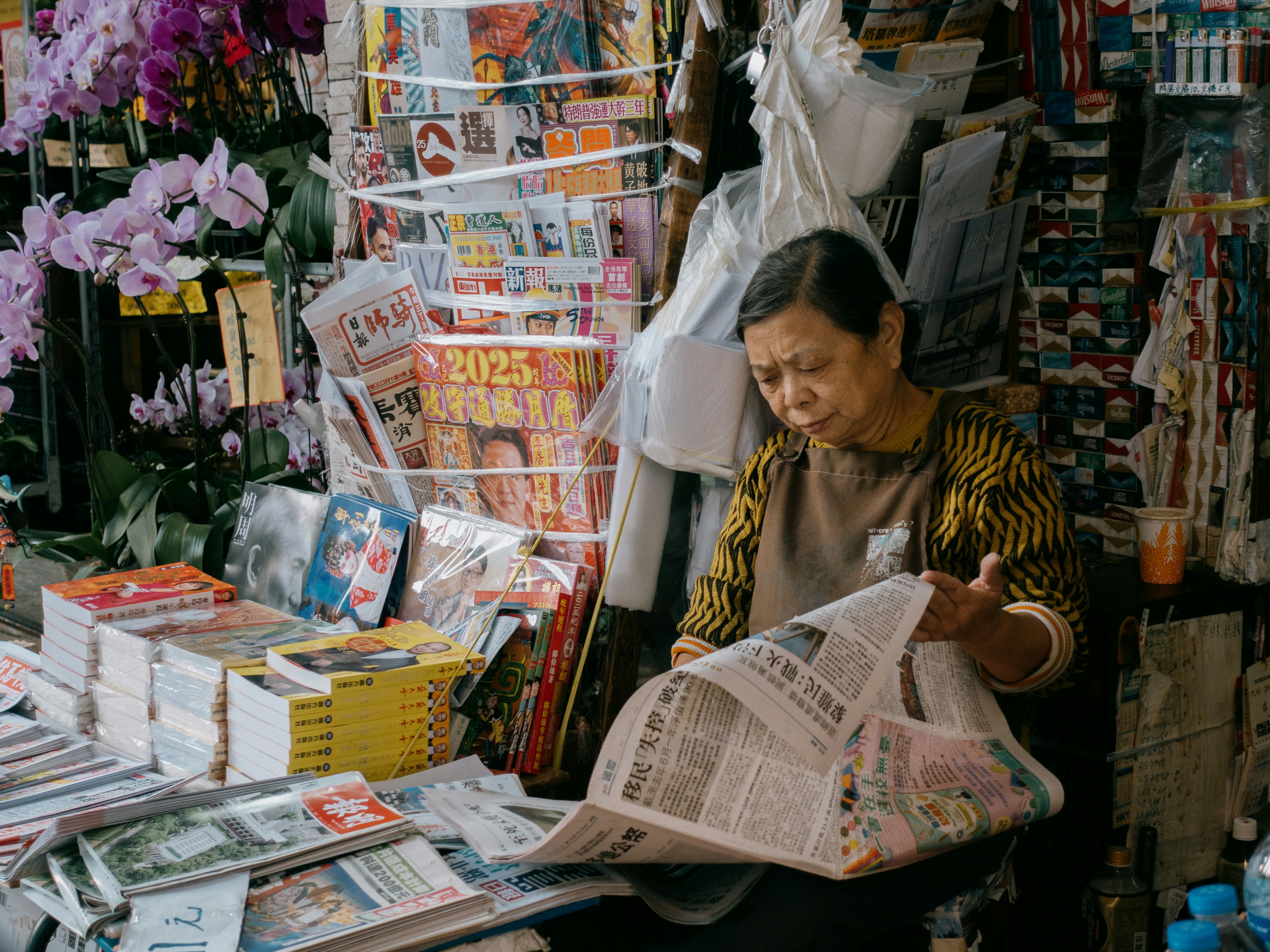 A woman sitting in a chair reading a newspaper photo – Free Street ...