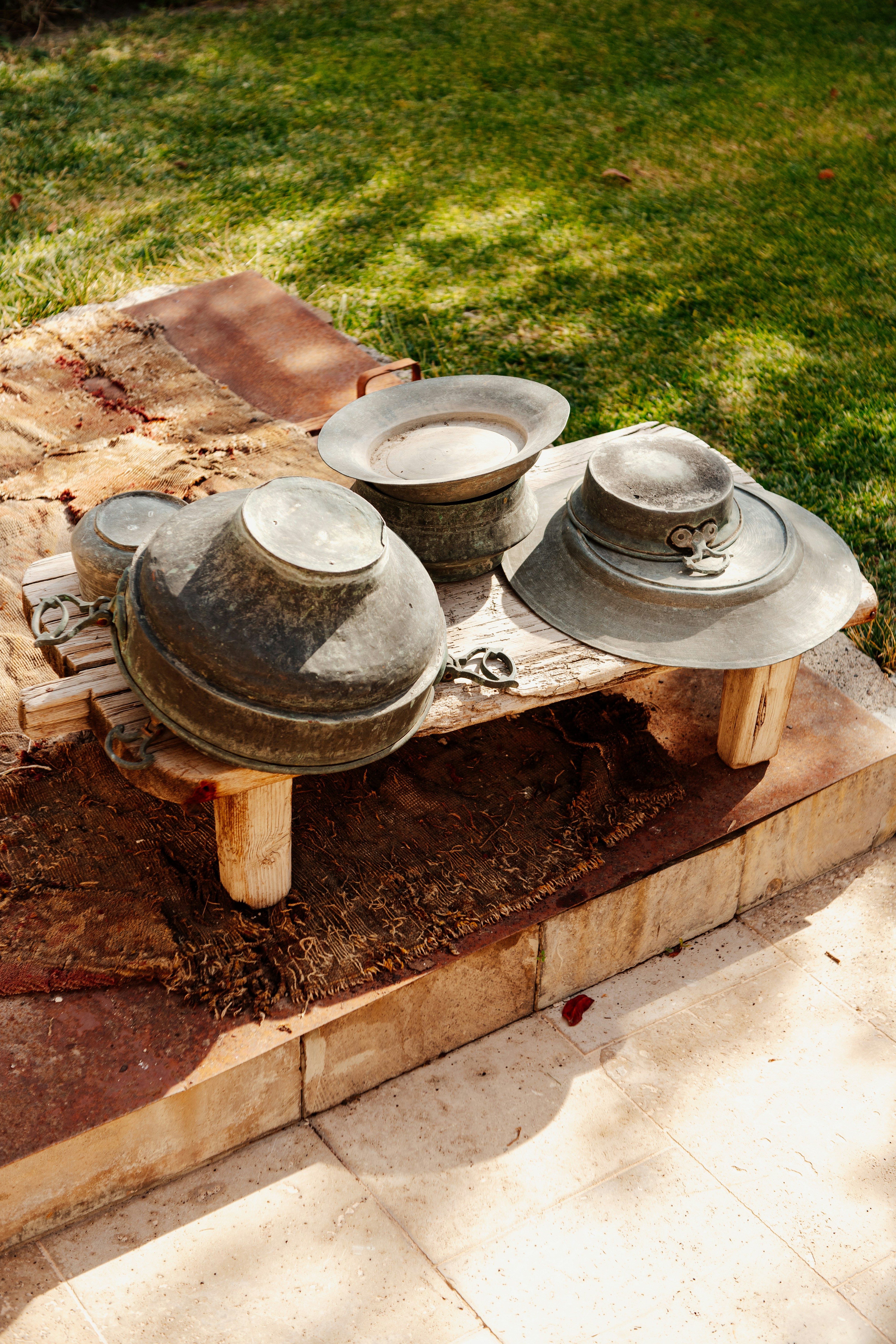 Weathered Metal Kettles on a Rustic Pedestal in Dappled Sunlight
