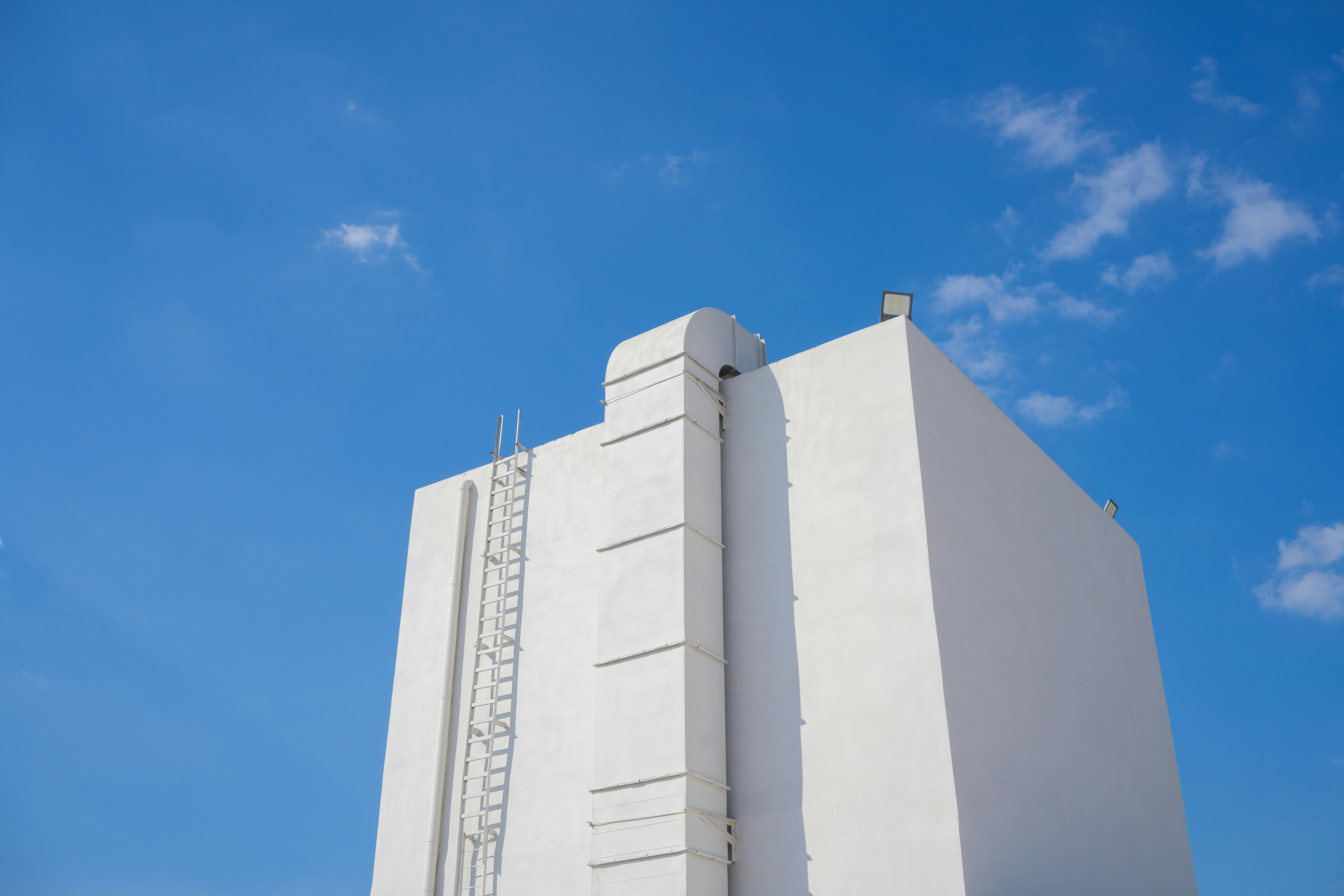 Ladder-Clad Facade Reaching Toward a Clear Blue Sky