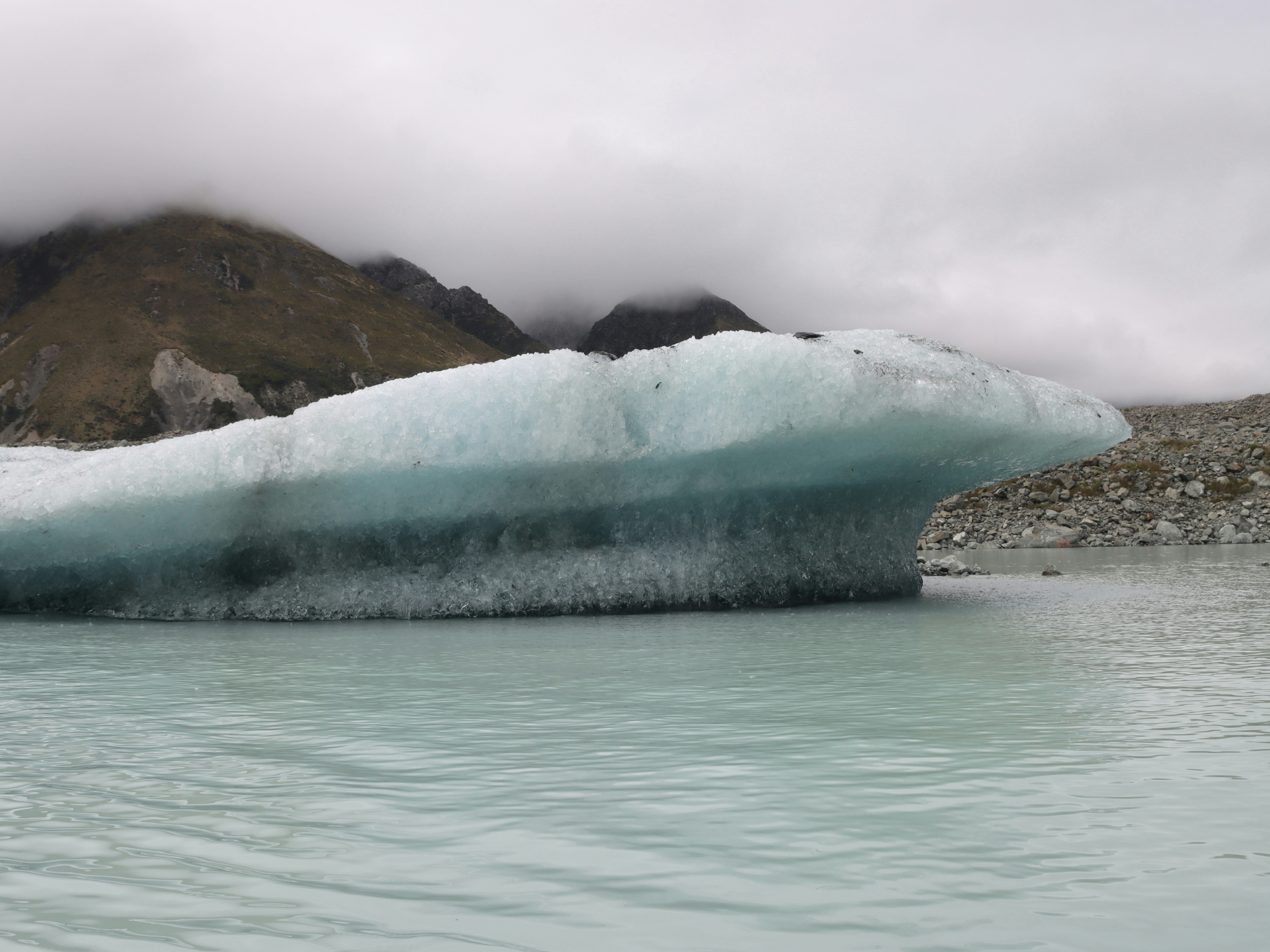 Turquoise Fjord Ice: A Lone Iceberg Anchored in Glassy Waters