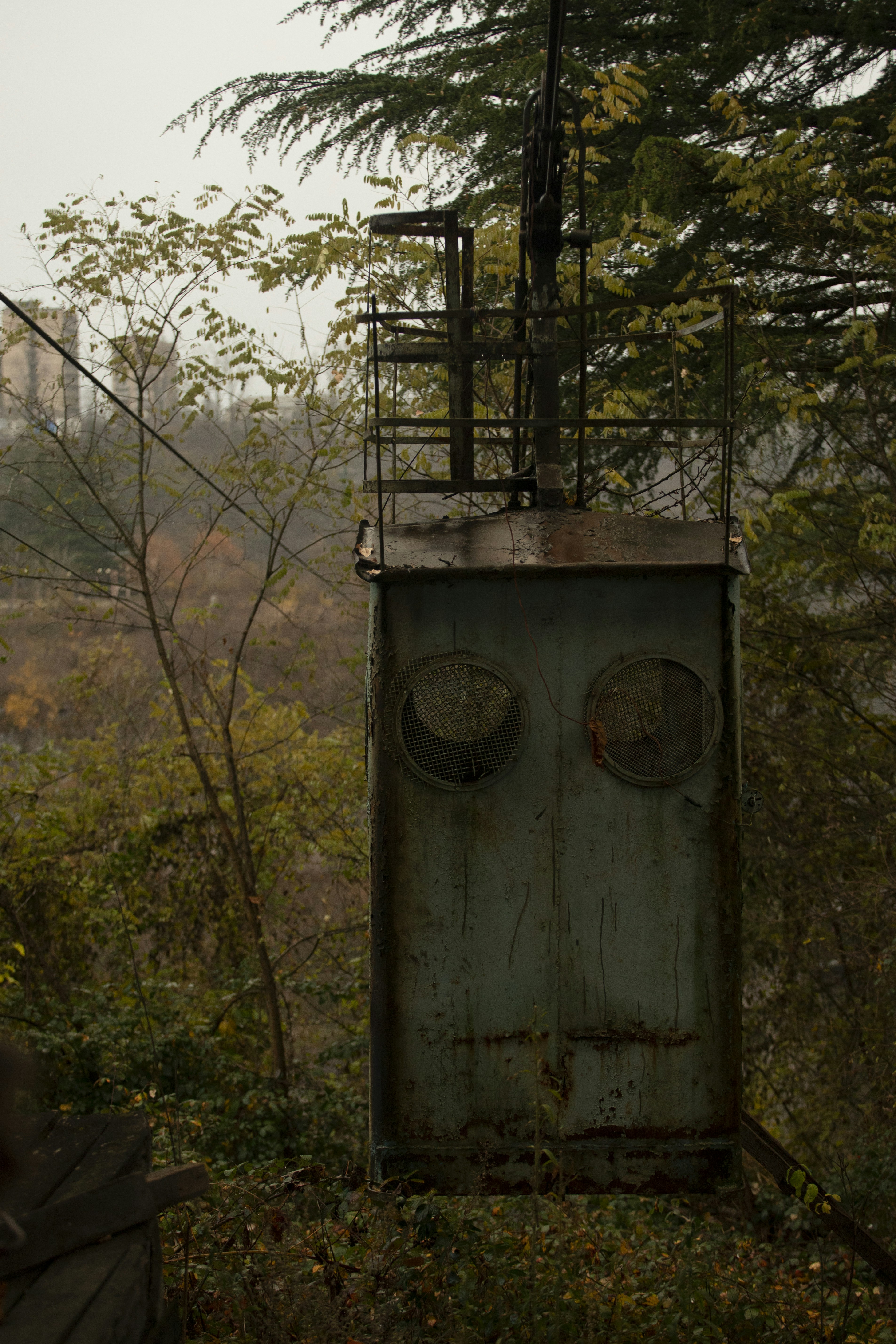 A rusted tower amid autumn woods with weathered vents
