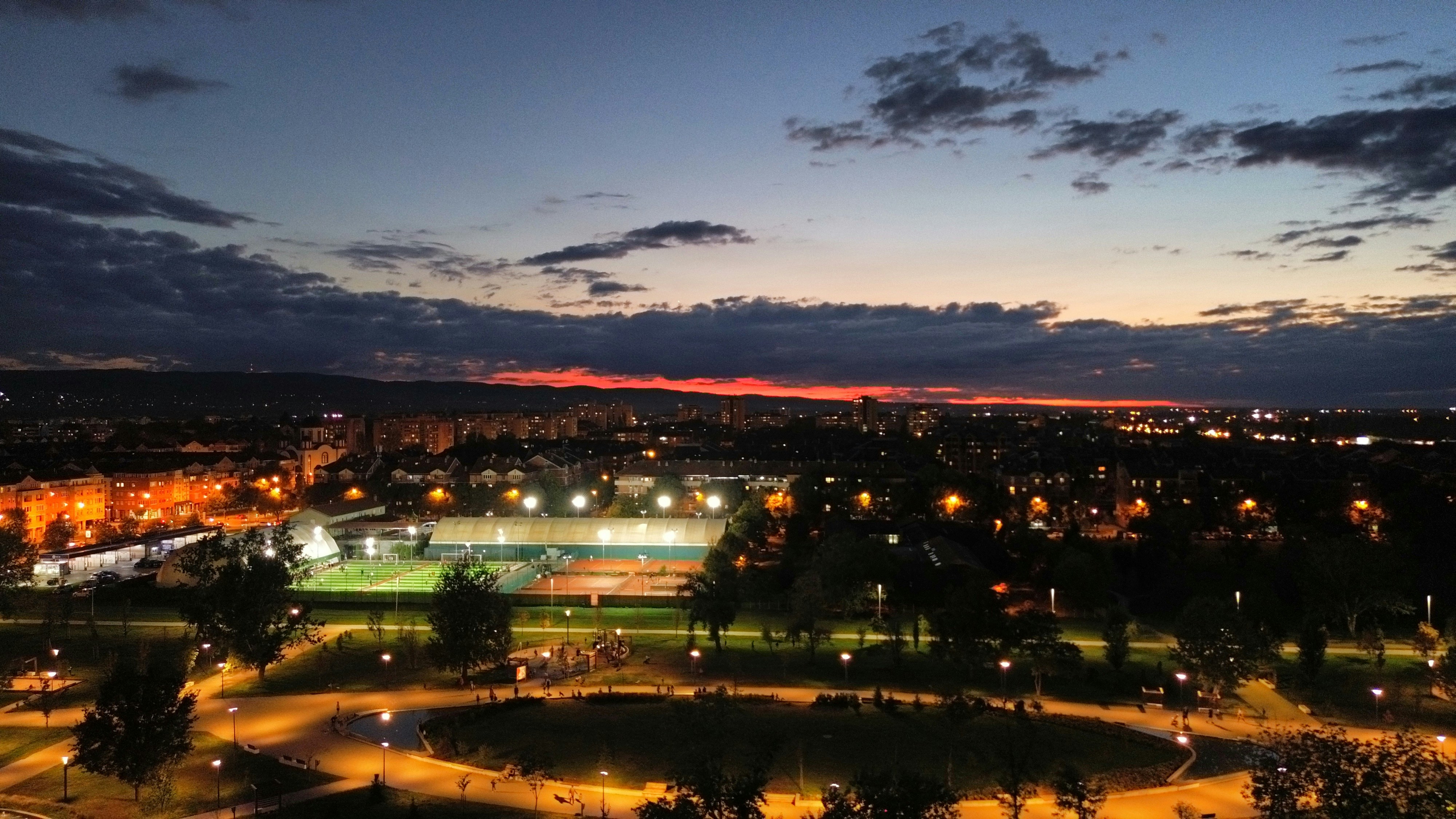 City lights twinkle under a deepening twilight sky as clouds drift above.