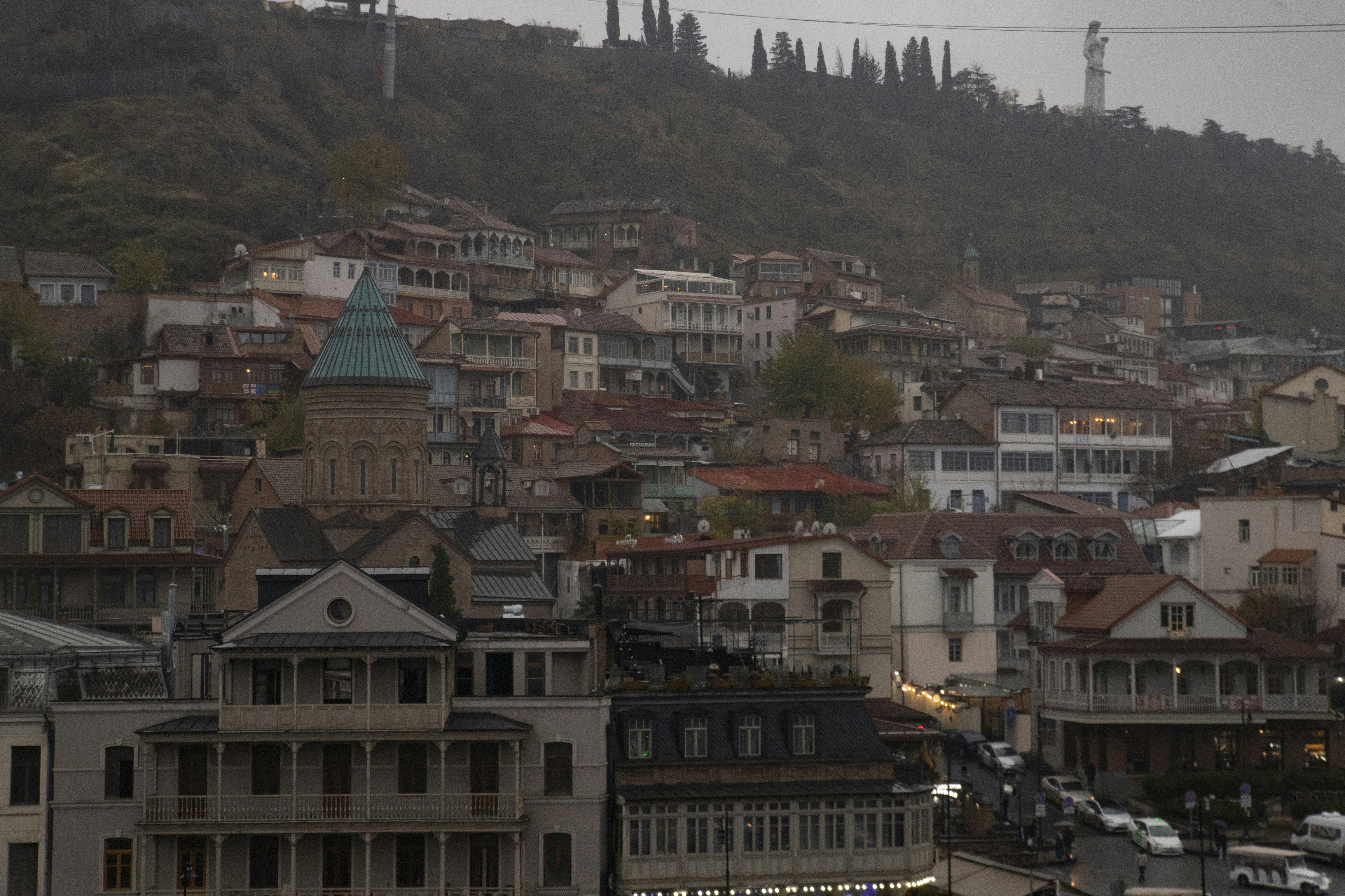 Overcast view of a densely populated hillside with historic buildings and lush greenery.