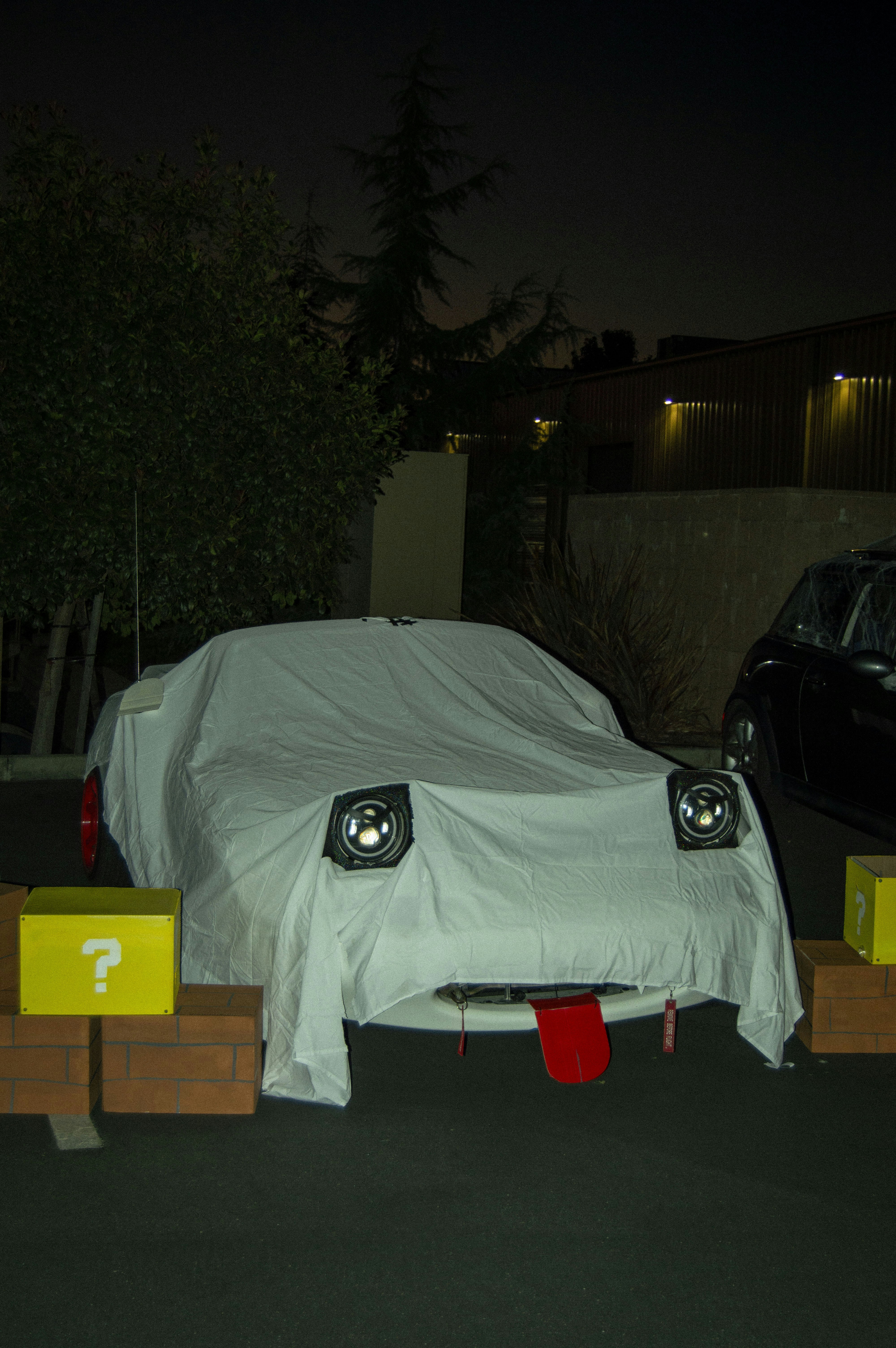 Twin-Headlight Reveal: A Covered Sports Car in a Dim Lot