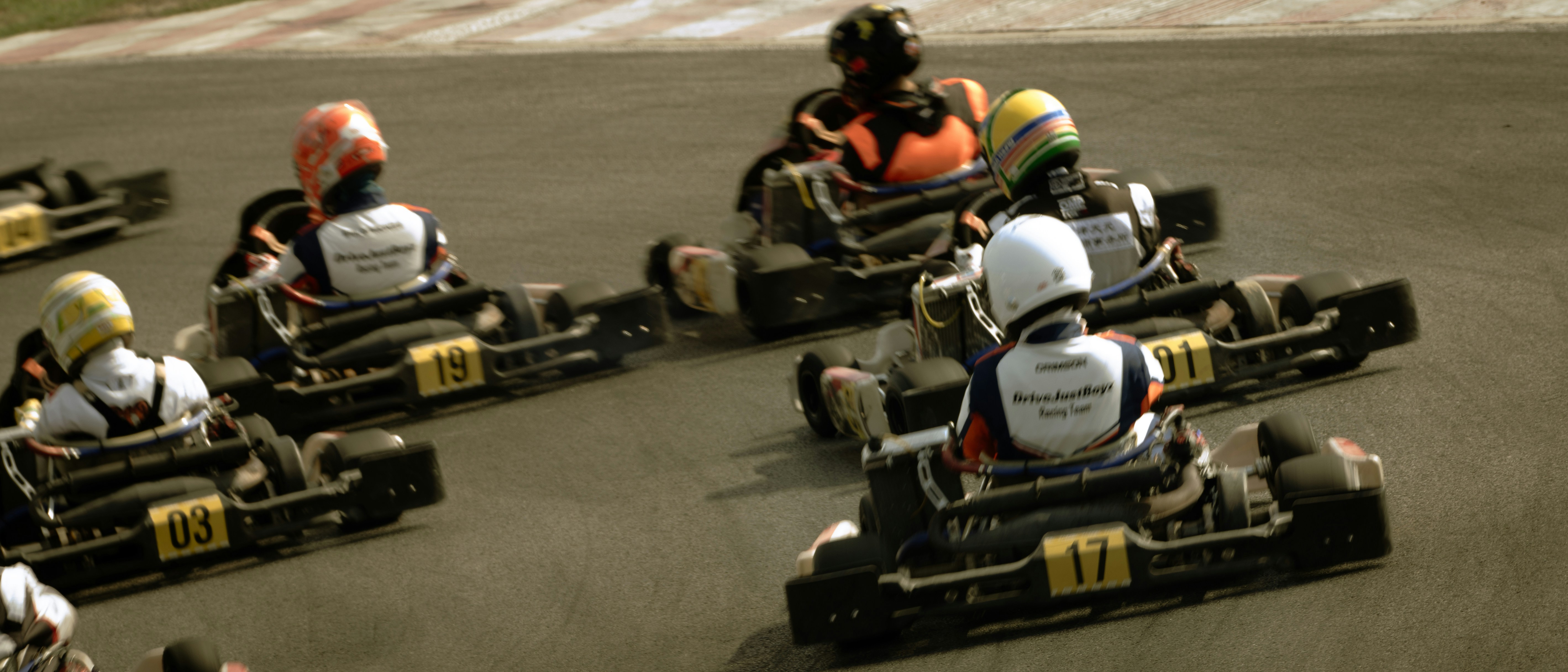A group of people racing go kart cars around a track photo – Free Kart ...