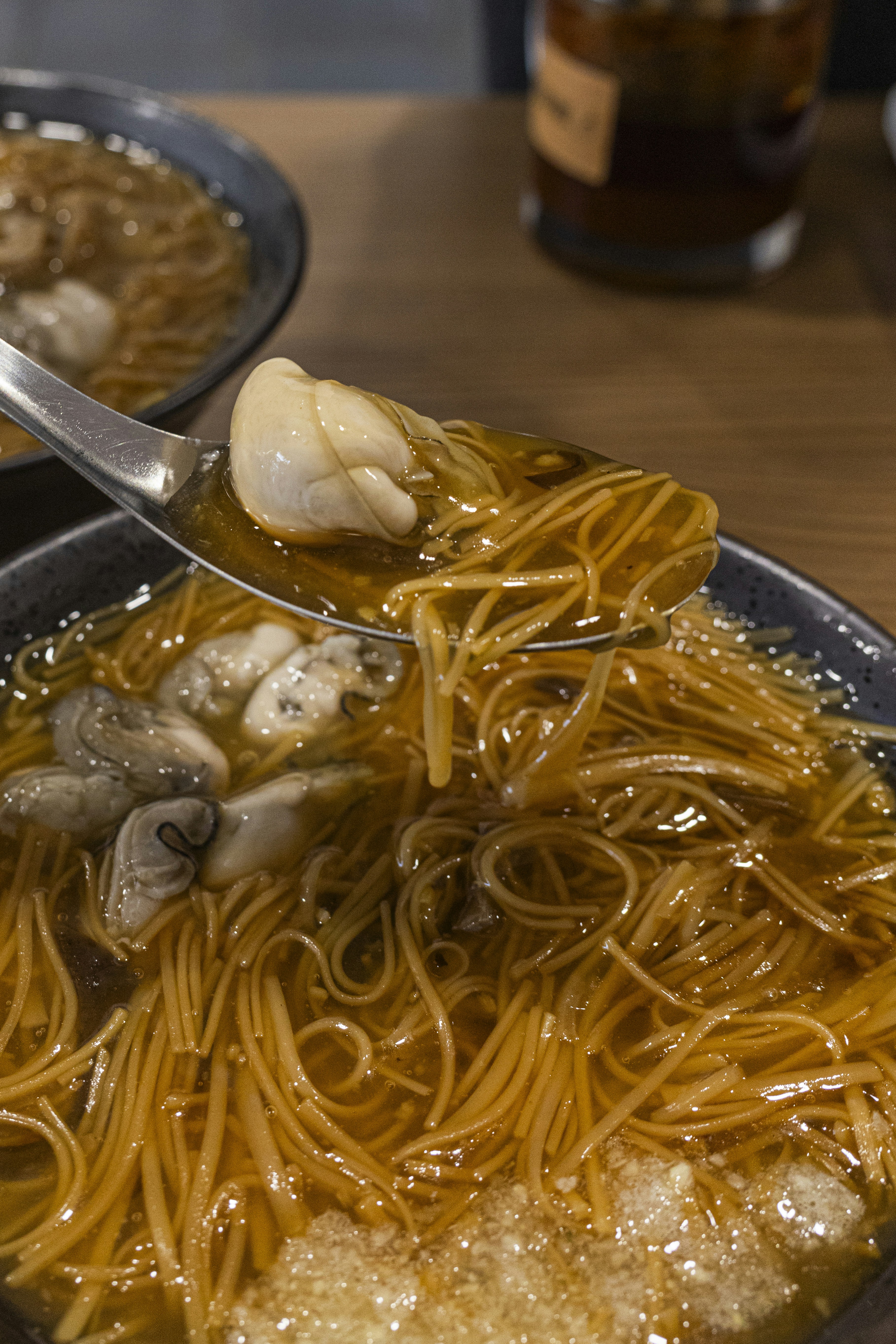 Clams on a Spoon Over Tangled Noodles in Amber Broth