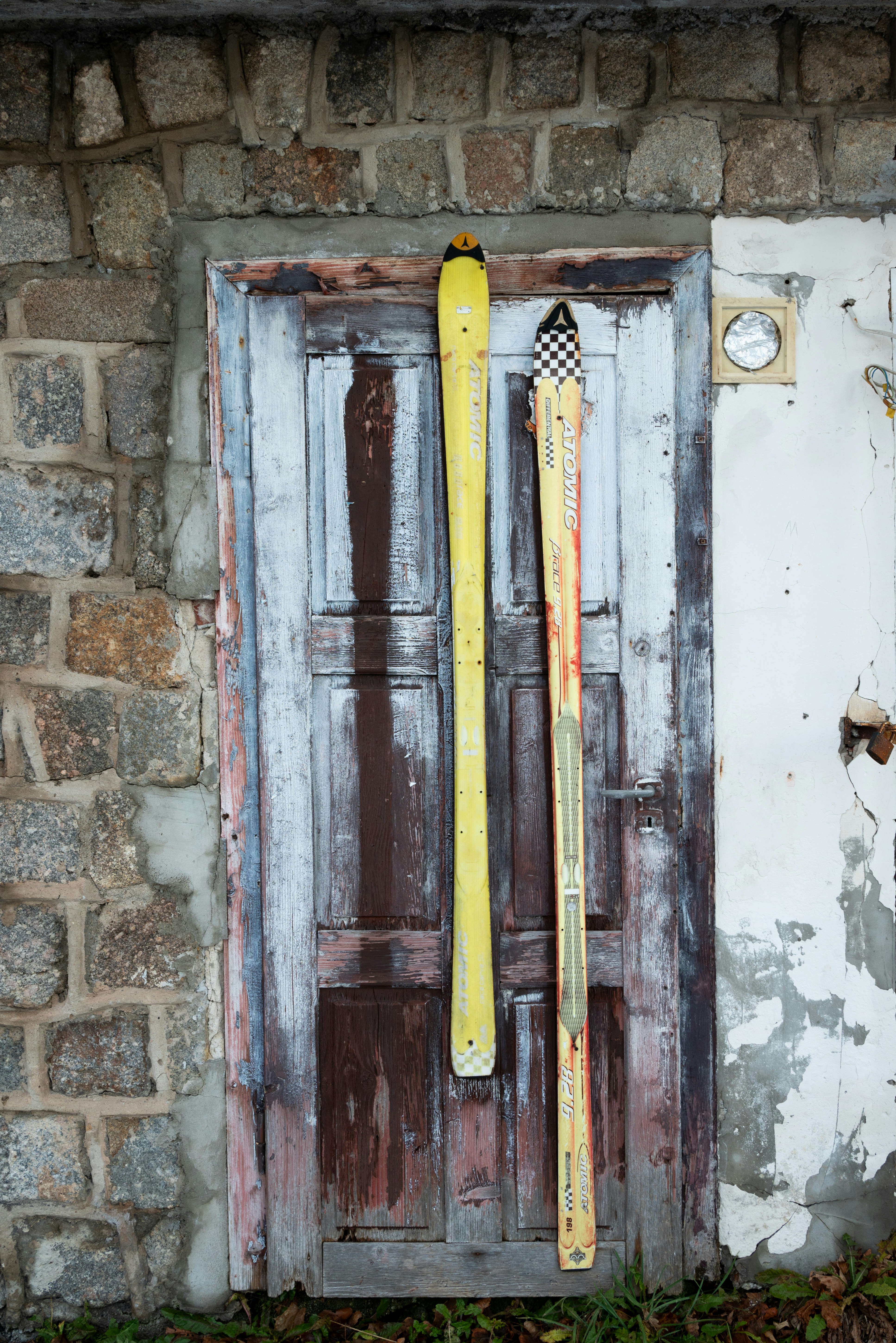 Two Vintage Skis Lean Against a Weathered Door: Quiet Winter Relic